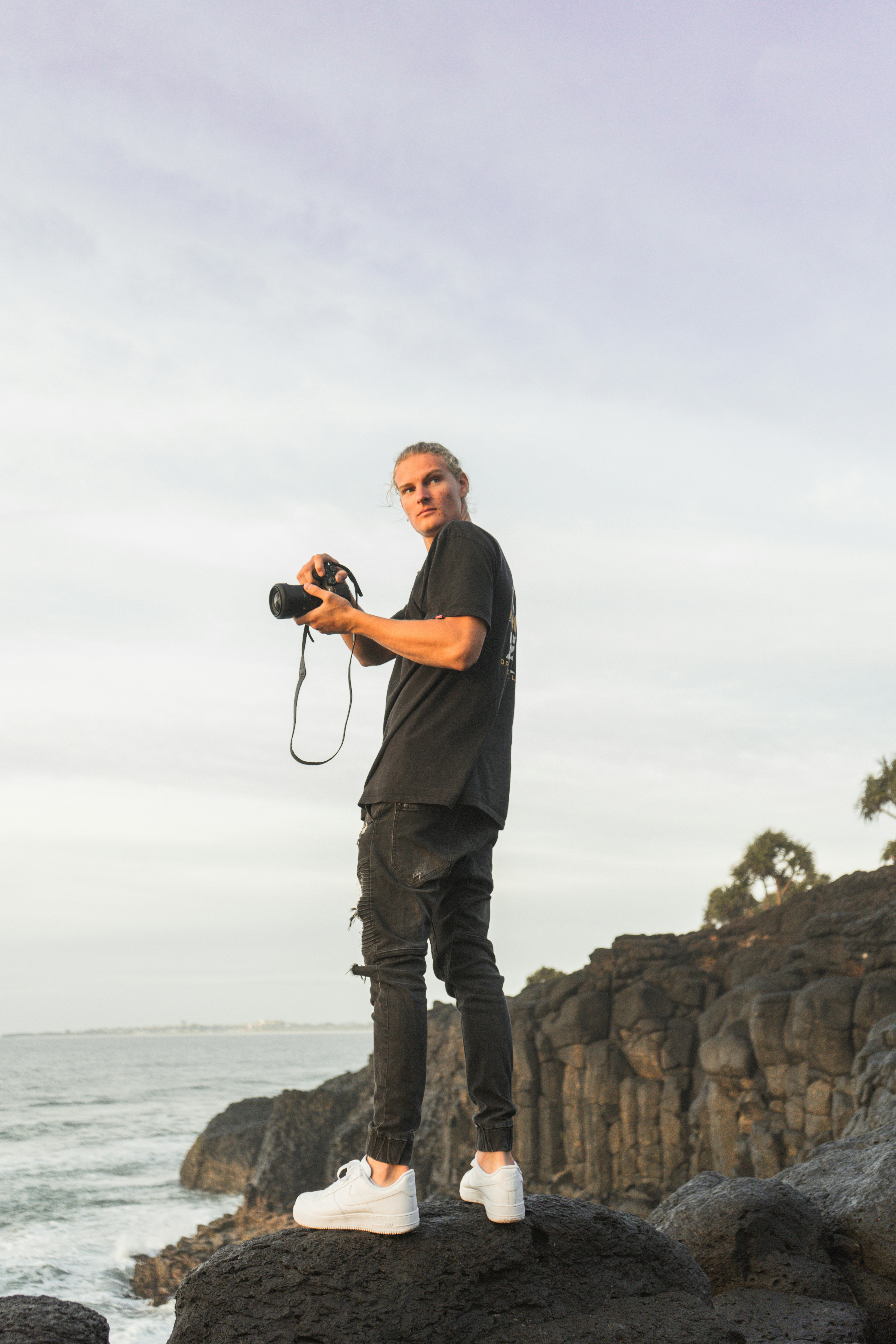Basalt Edge Portrait: A Lone Photographer Pauses on Coastal Rocks