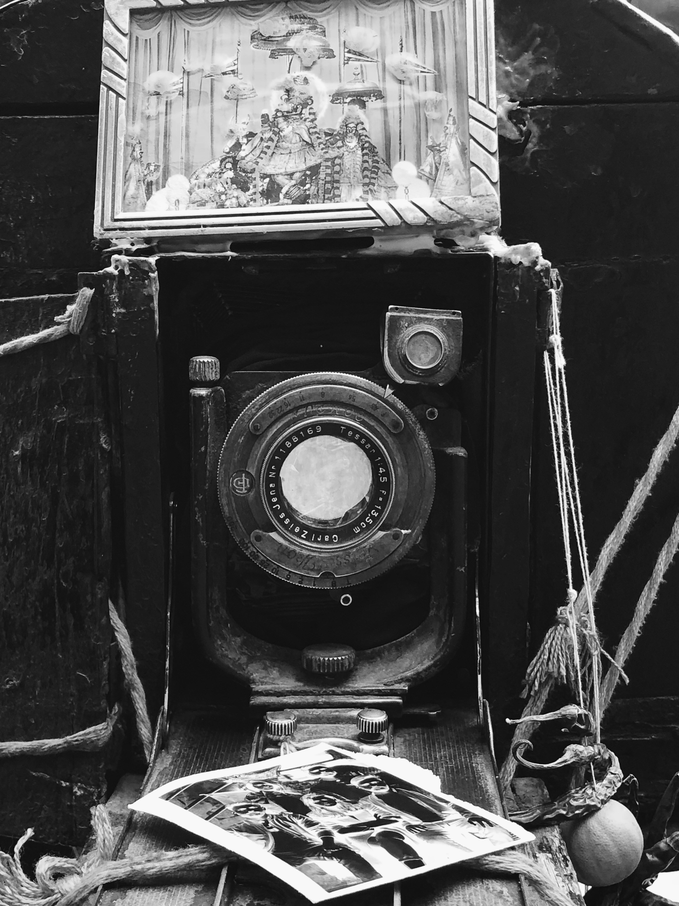 Antique camera with a detailed lens and historical photographs laid out in front, showcasing the evolution of photography. A decorative box sits atop, adding to the nostalgic atmosphere.