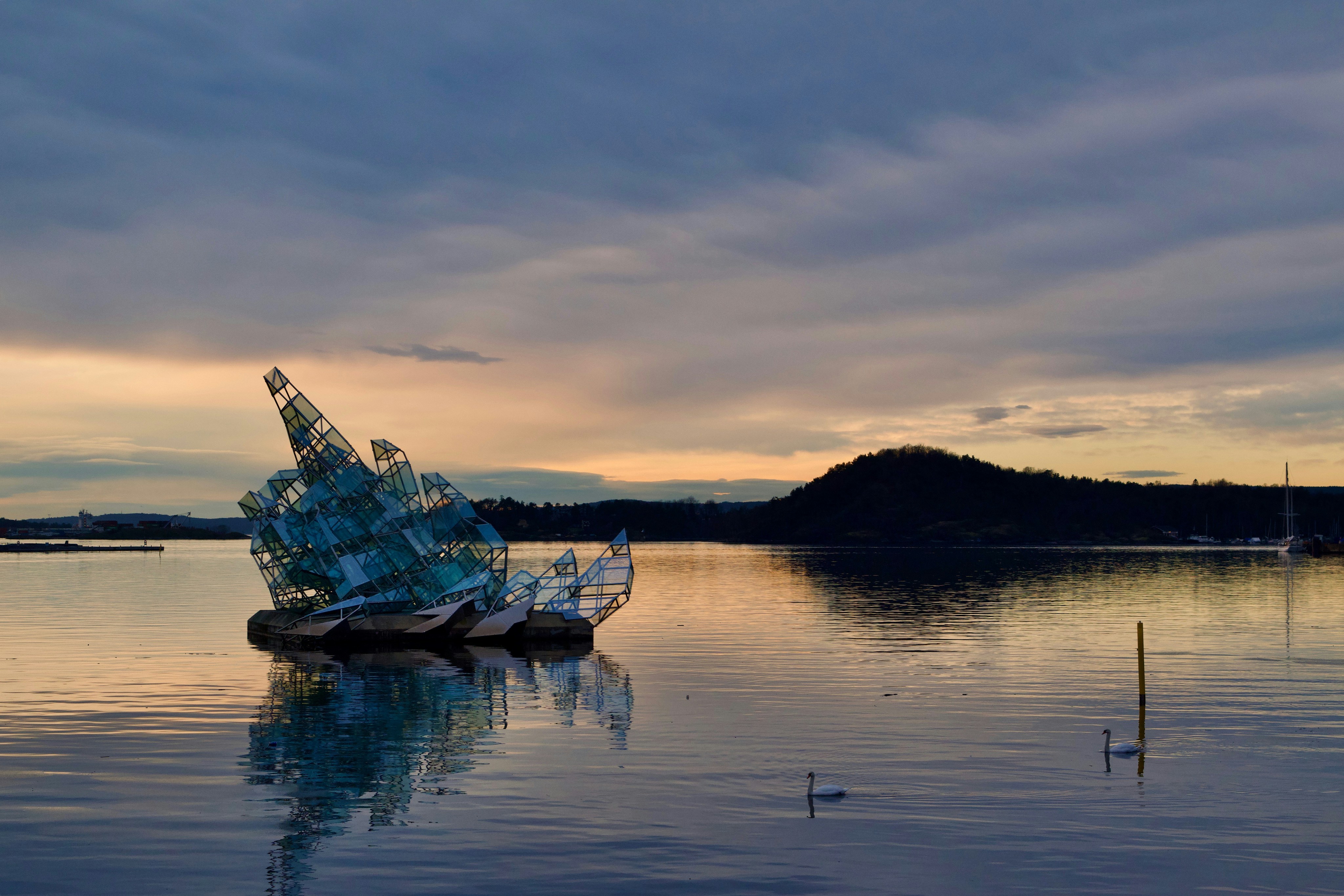 Jagged ice formations float serenely on a calm sea as dusk paints the sky with subtle hues.
