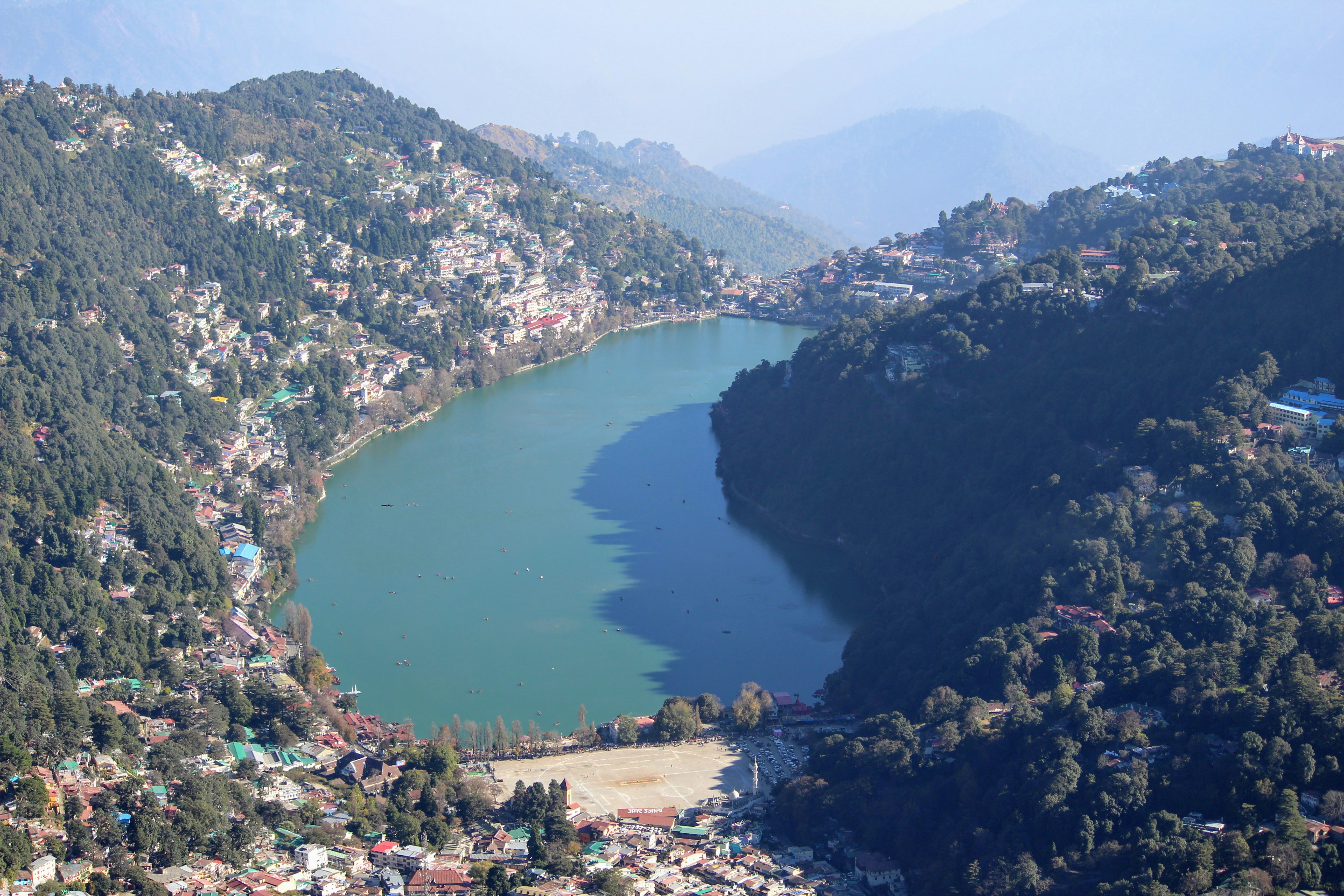 Naina Peak, being the highest hill-top offers this splendid Bird's eye view of the Nainital town, the Himalayas and also the vast expanses of the Kumaon region. | aerial view of green mountains and body of water during daytime