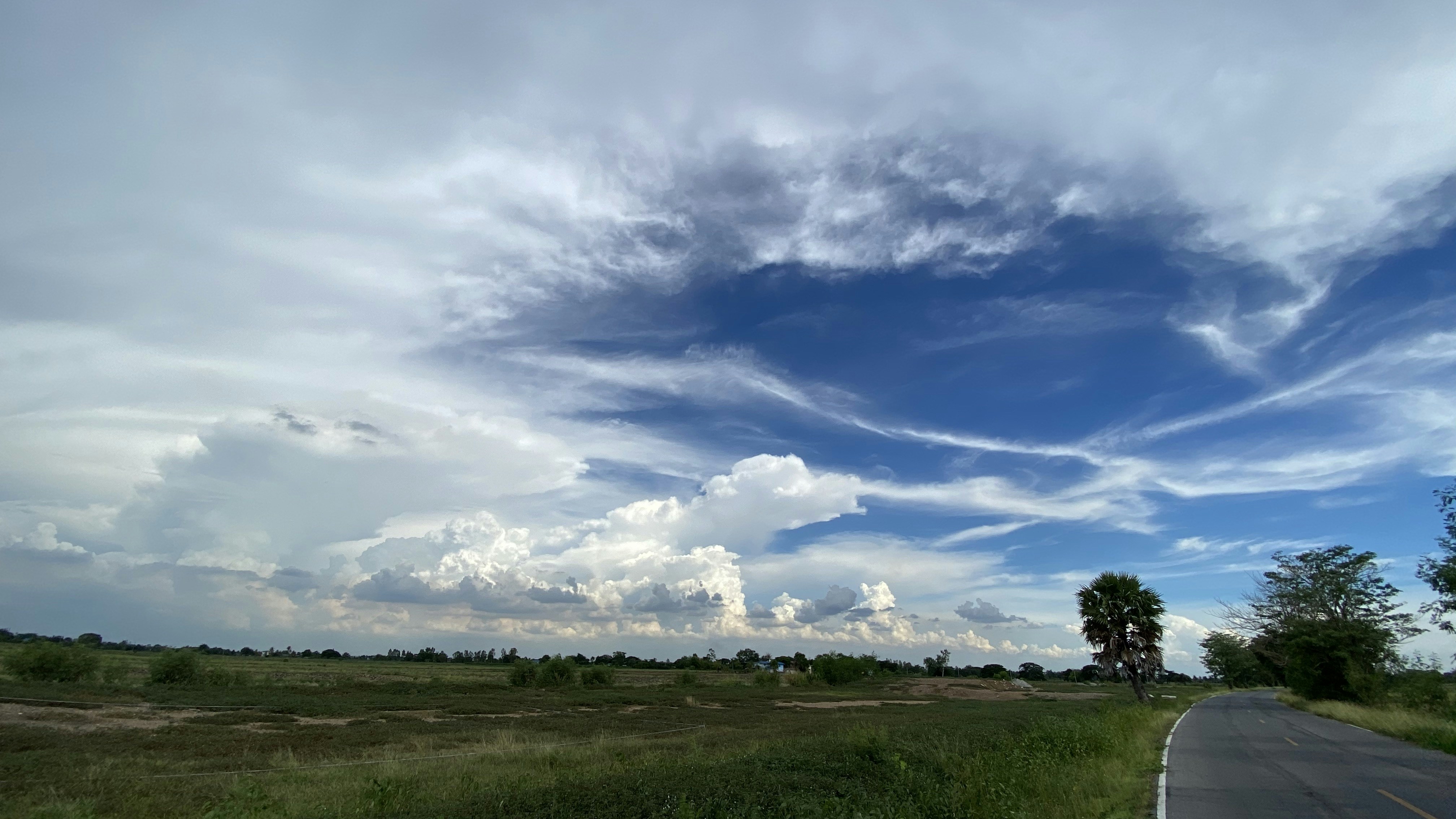 Expansive landscape under a dramatic sky with swirling clouds and a distant horizon.