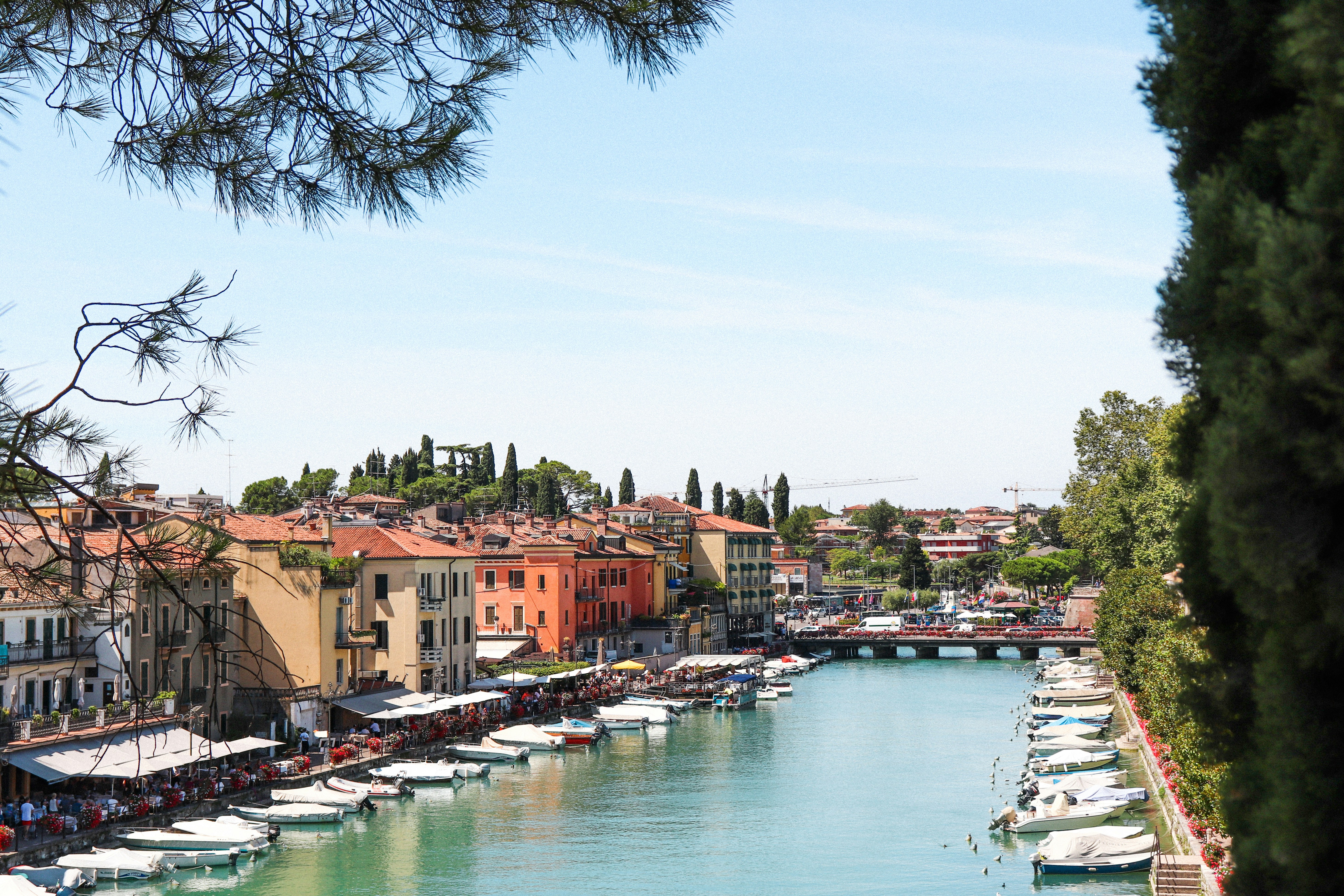 Colorful buildings and boats along a tranquil canal under a clear sky.