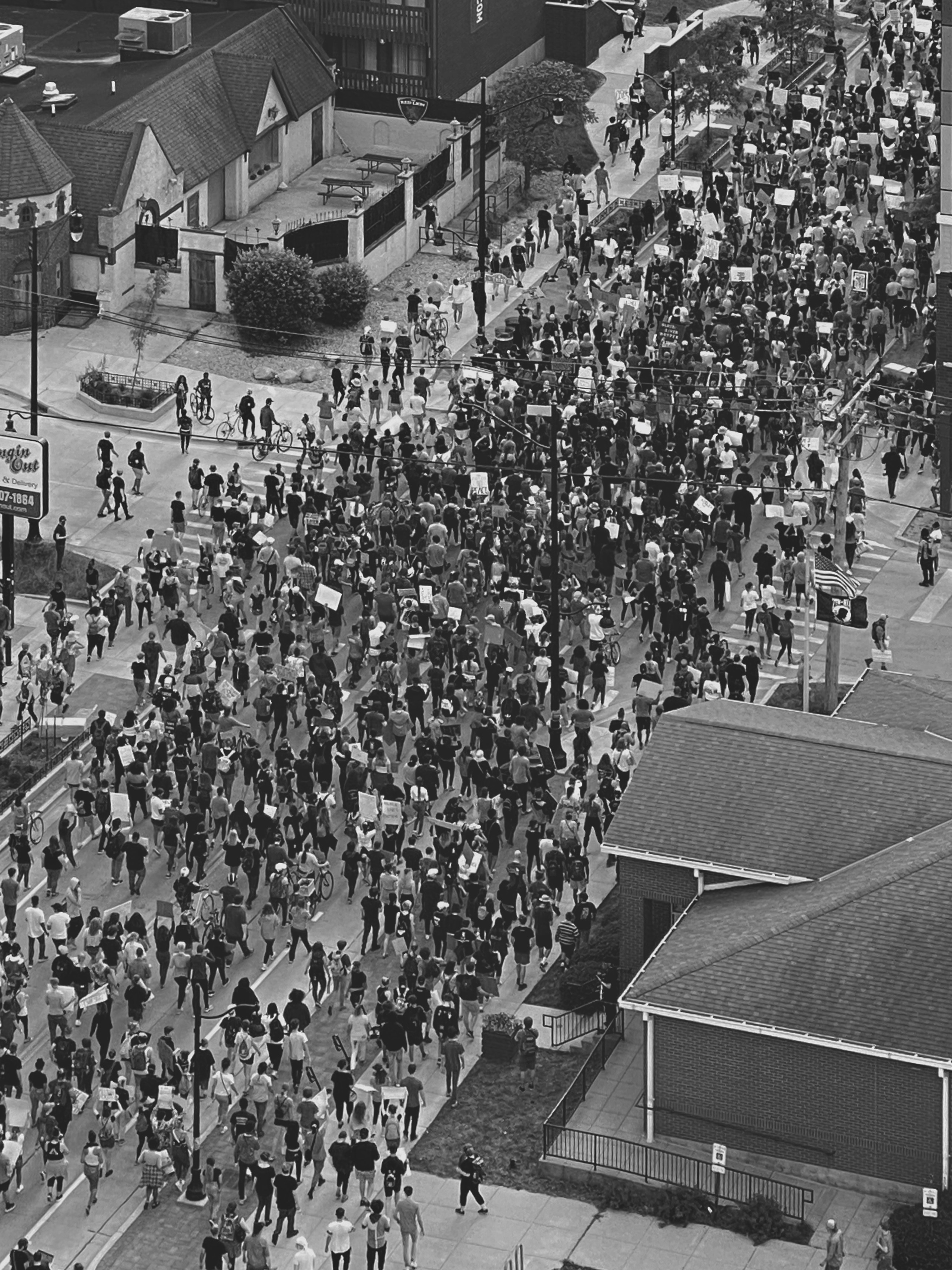 Massive crowd gathered on city streets, holding signs and marching together in solidarity. Black and white capture emphasizes the movement's energy.