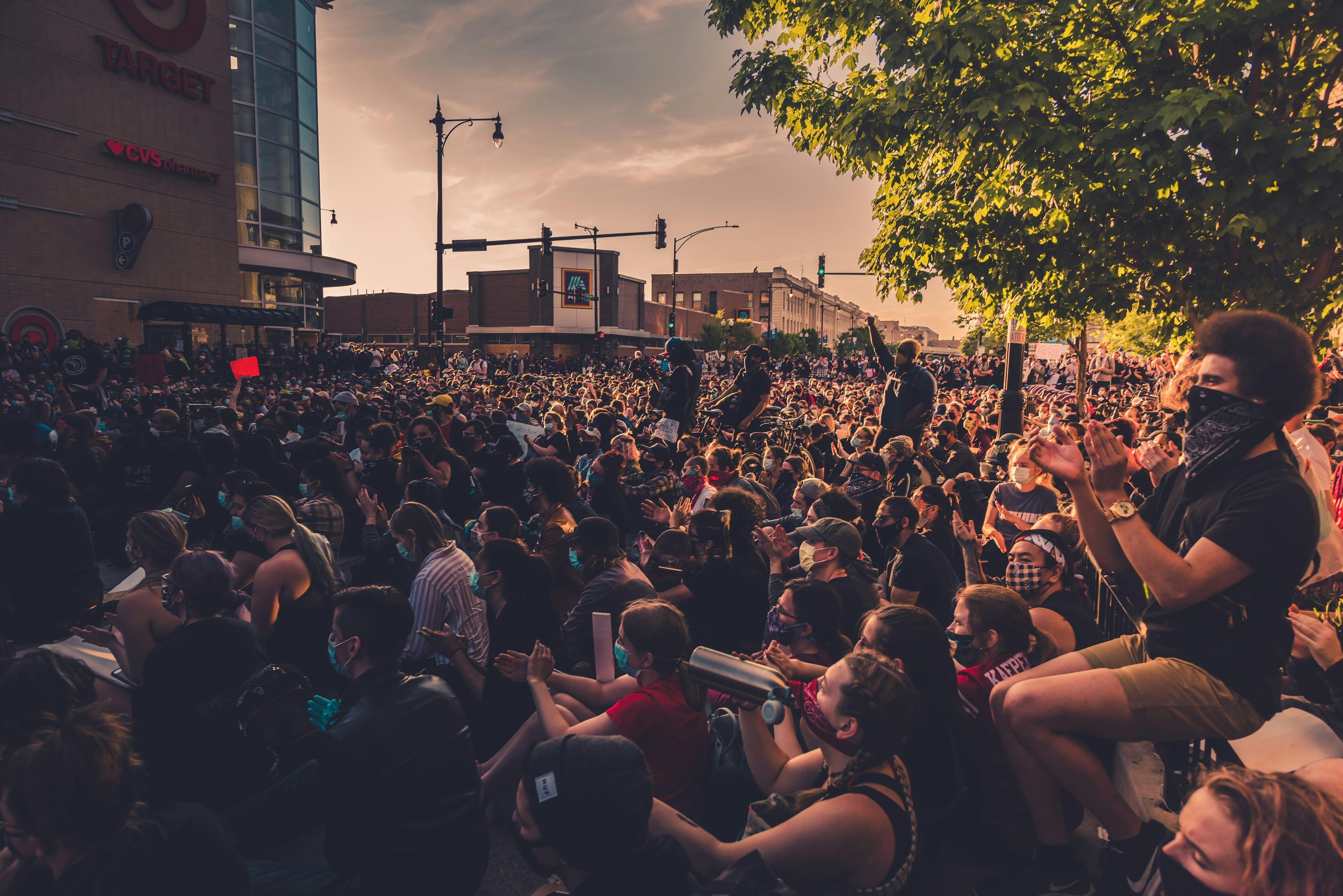 Large crowd gathered in front of a store, expressing solidarity and activism during a protest. The scene captures the intensity of the moment.