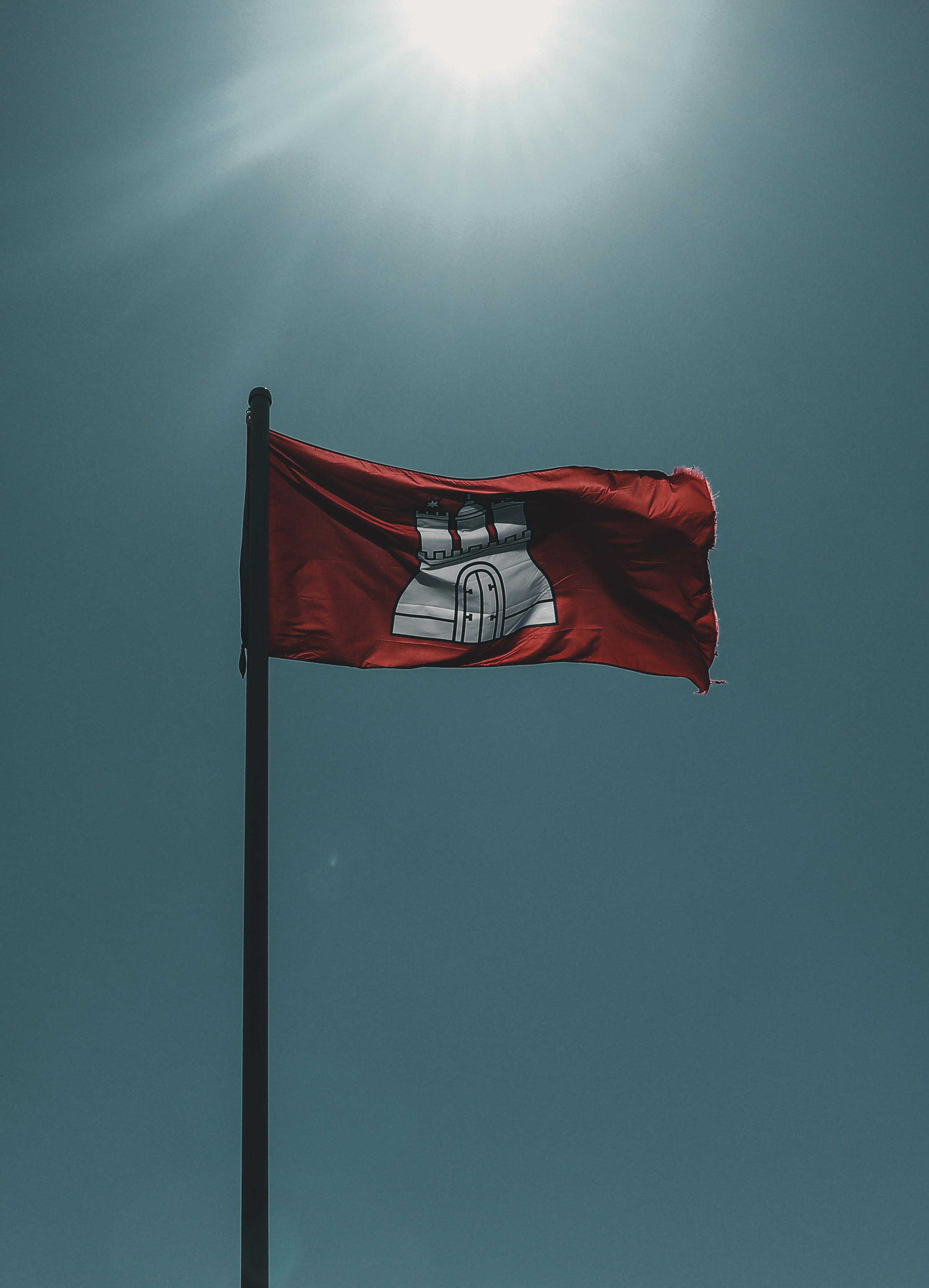 Crimson Flag on a Lone Mast Under a Noonday Sky