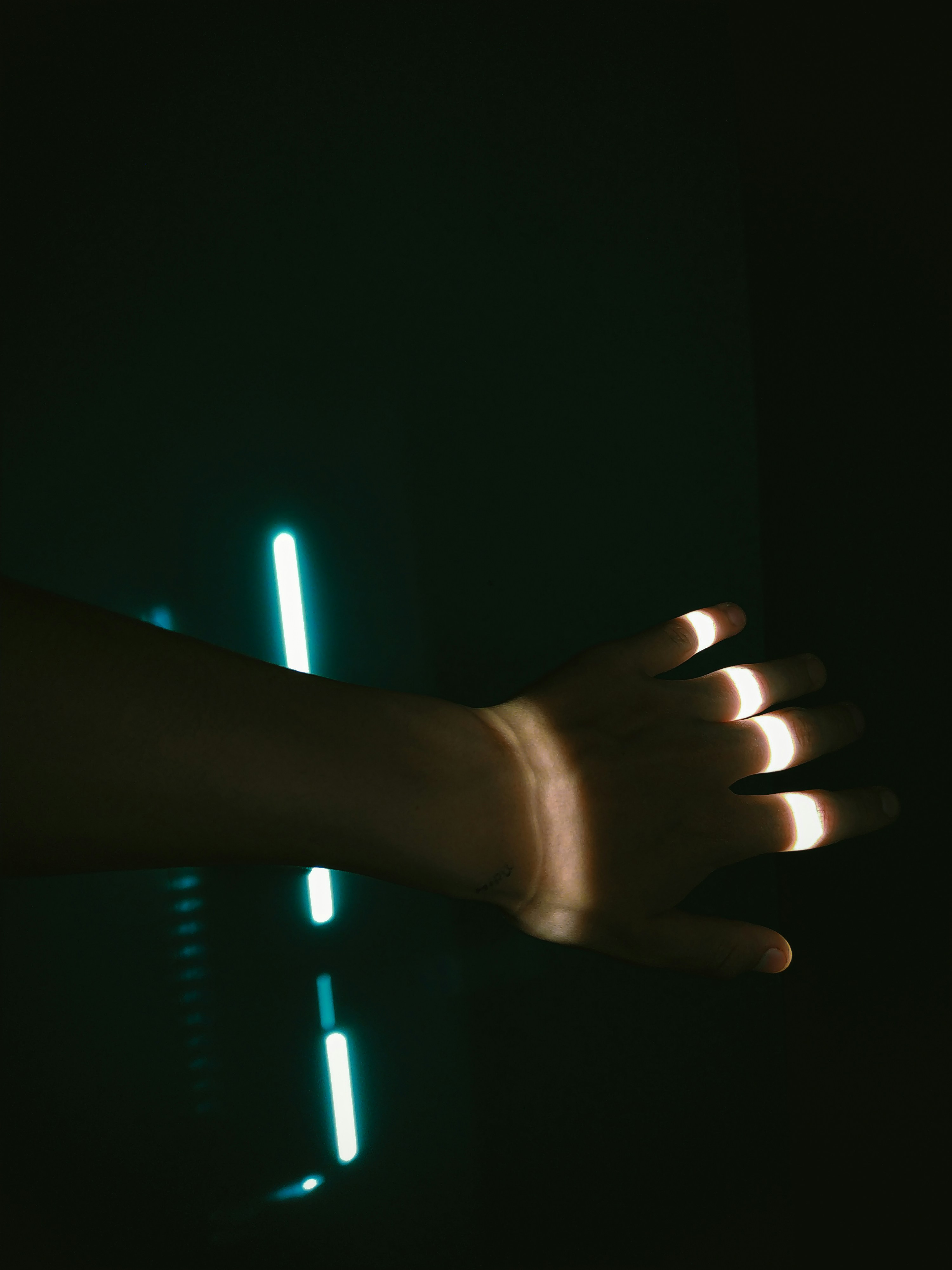 Cyan Neon Traces: A Hand Emerges in the Dark