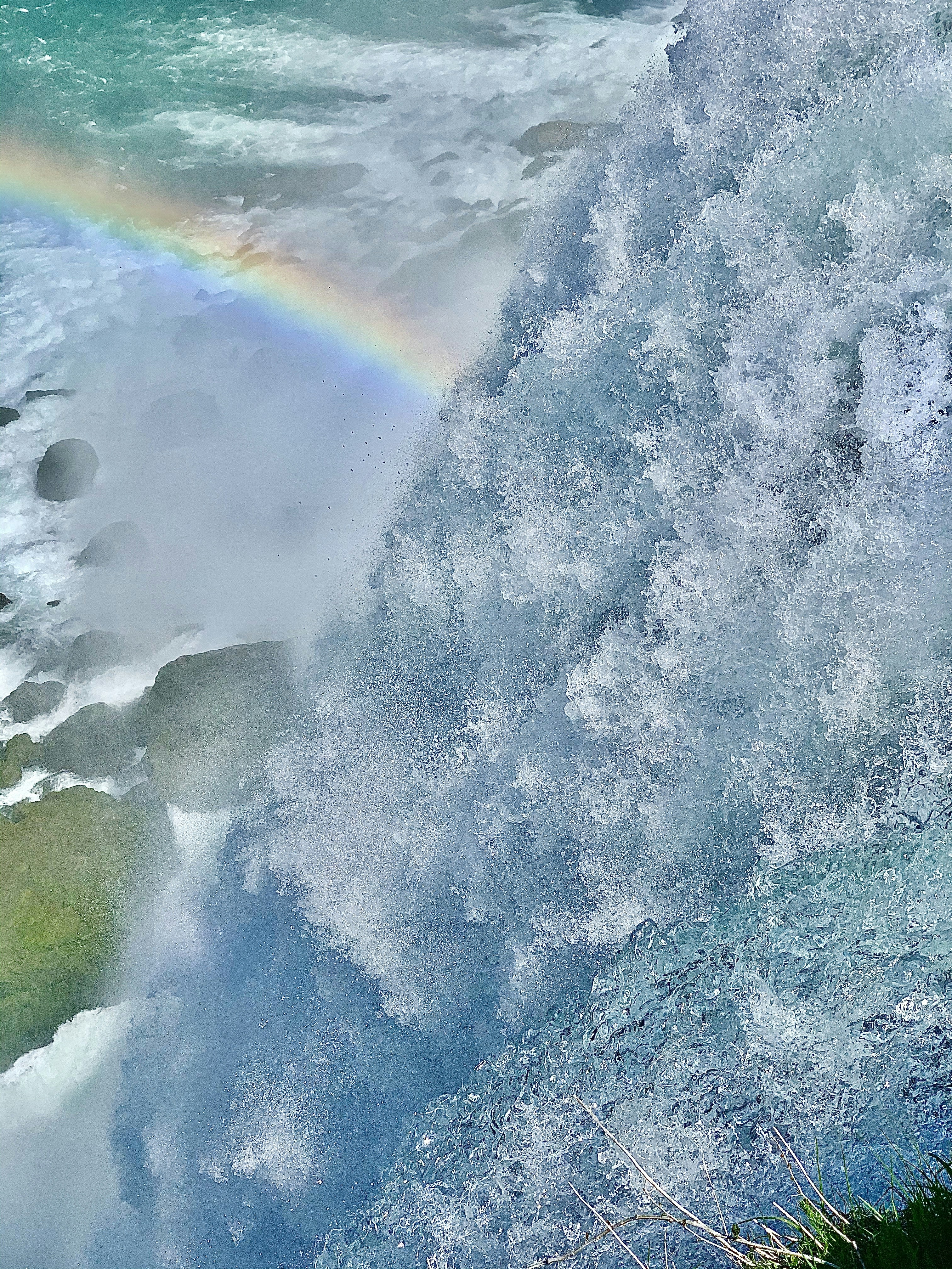 Vibrant waterfall cascading over rocks with a rainbow forming in the mist. The dynamic movement of water creates a lively atmosphere.