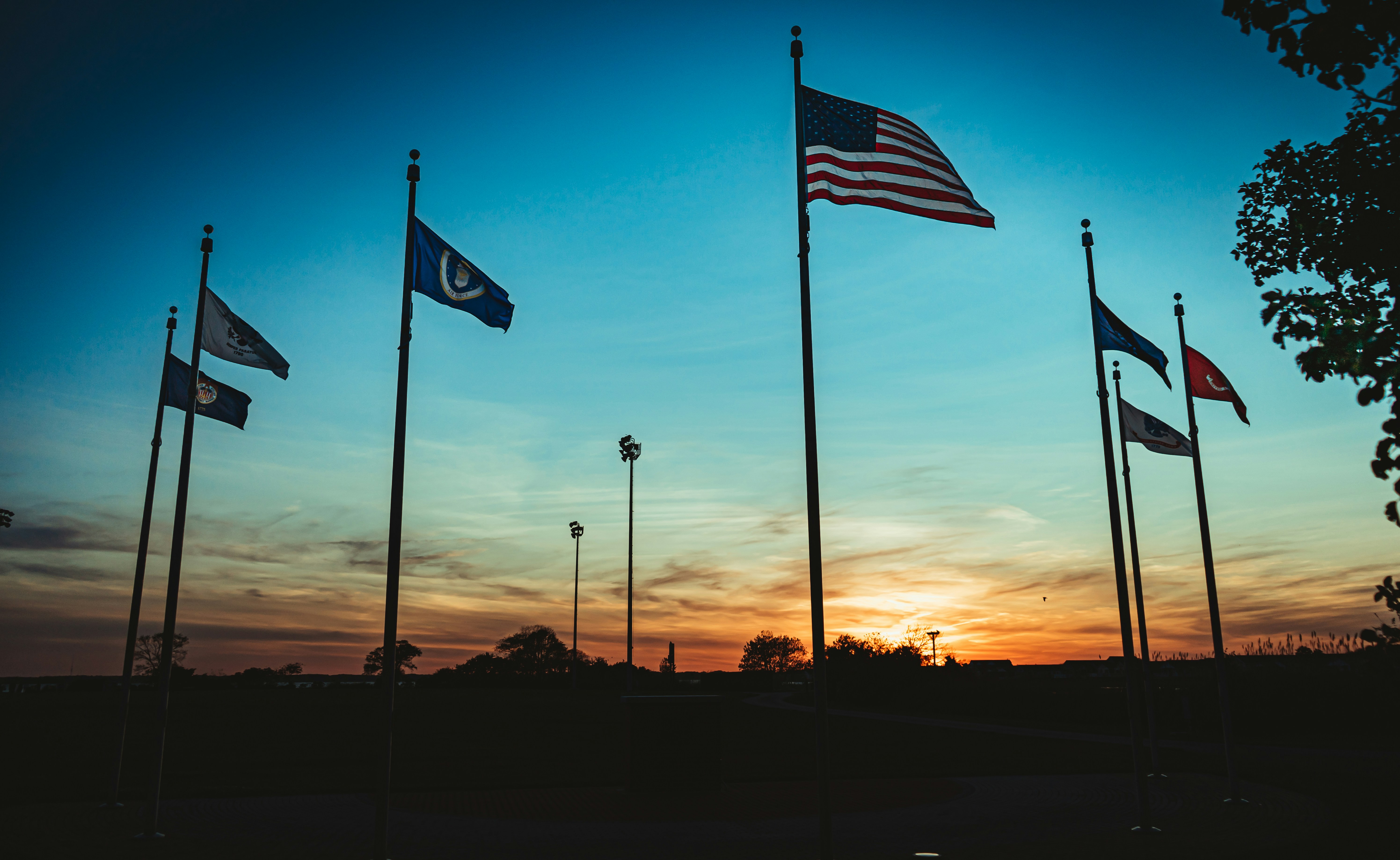 Silhouetted flags stand tall against a vibrant sunset sky, capturing a moment of tranquility and pride.
