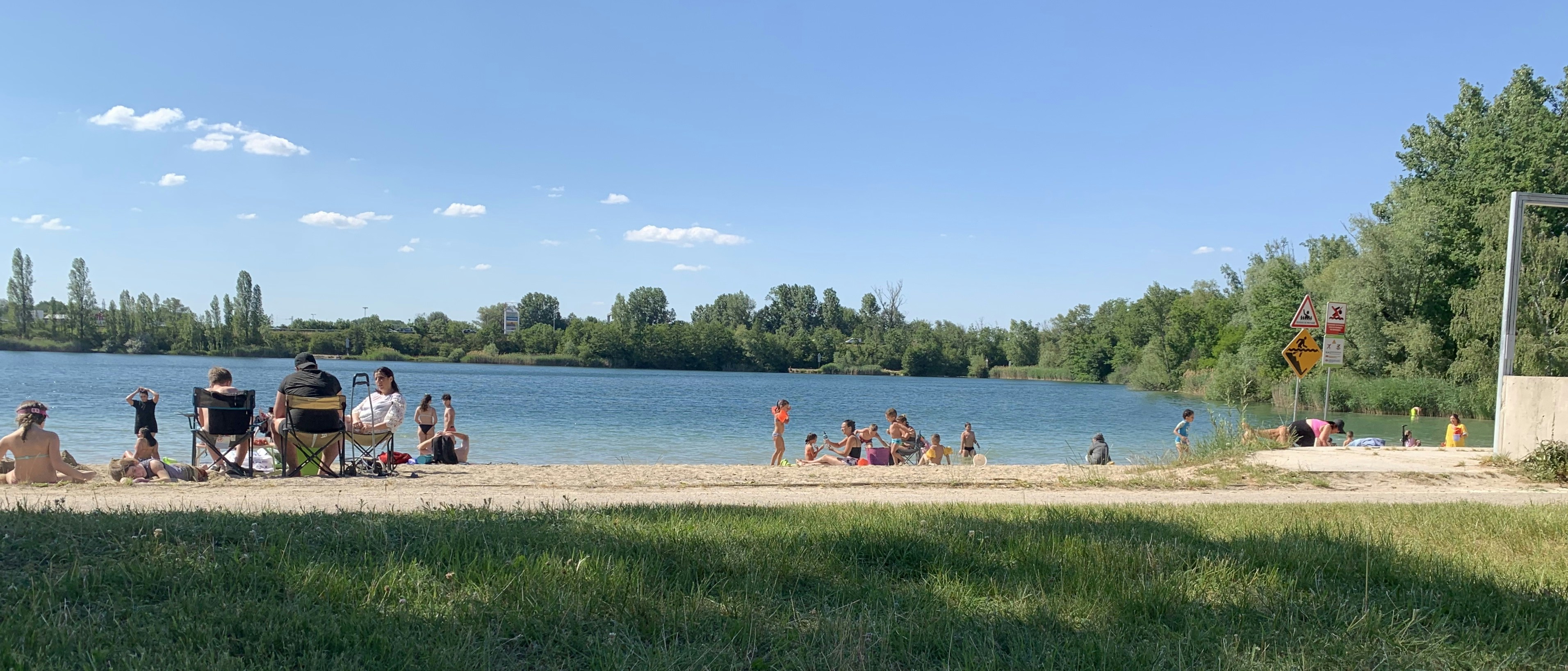 Sunlit shoreline: families and swimmers along a calm lakeside