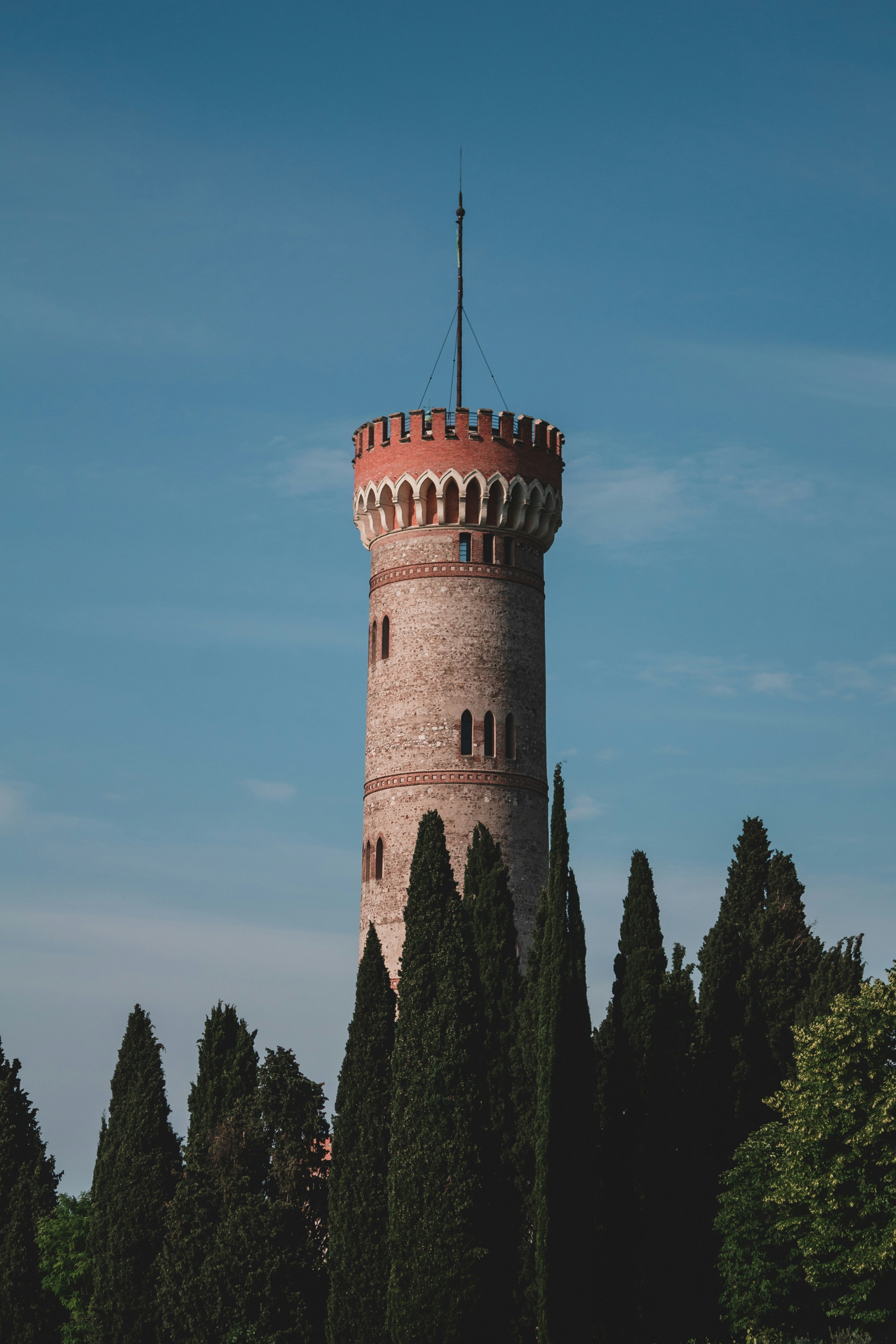Brown concrete tower surrounded by trees under blue sky during daytime ...