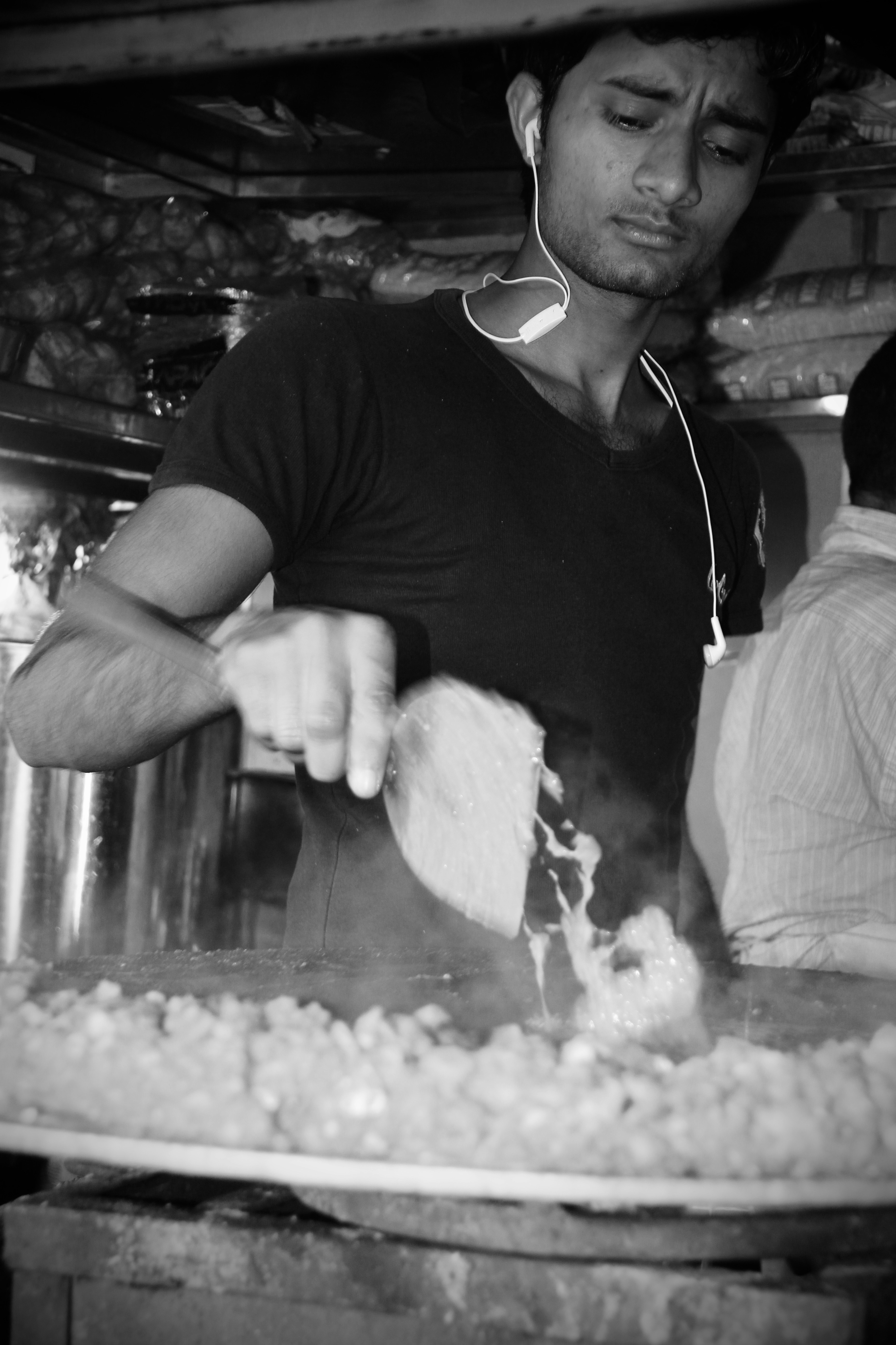 A chef skillfully preparing a dish in a bustling kitchen, with steam rising from the cooking surface. The scene captures the essence of street food culture.