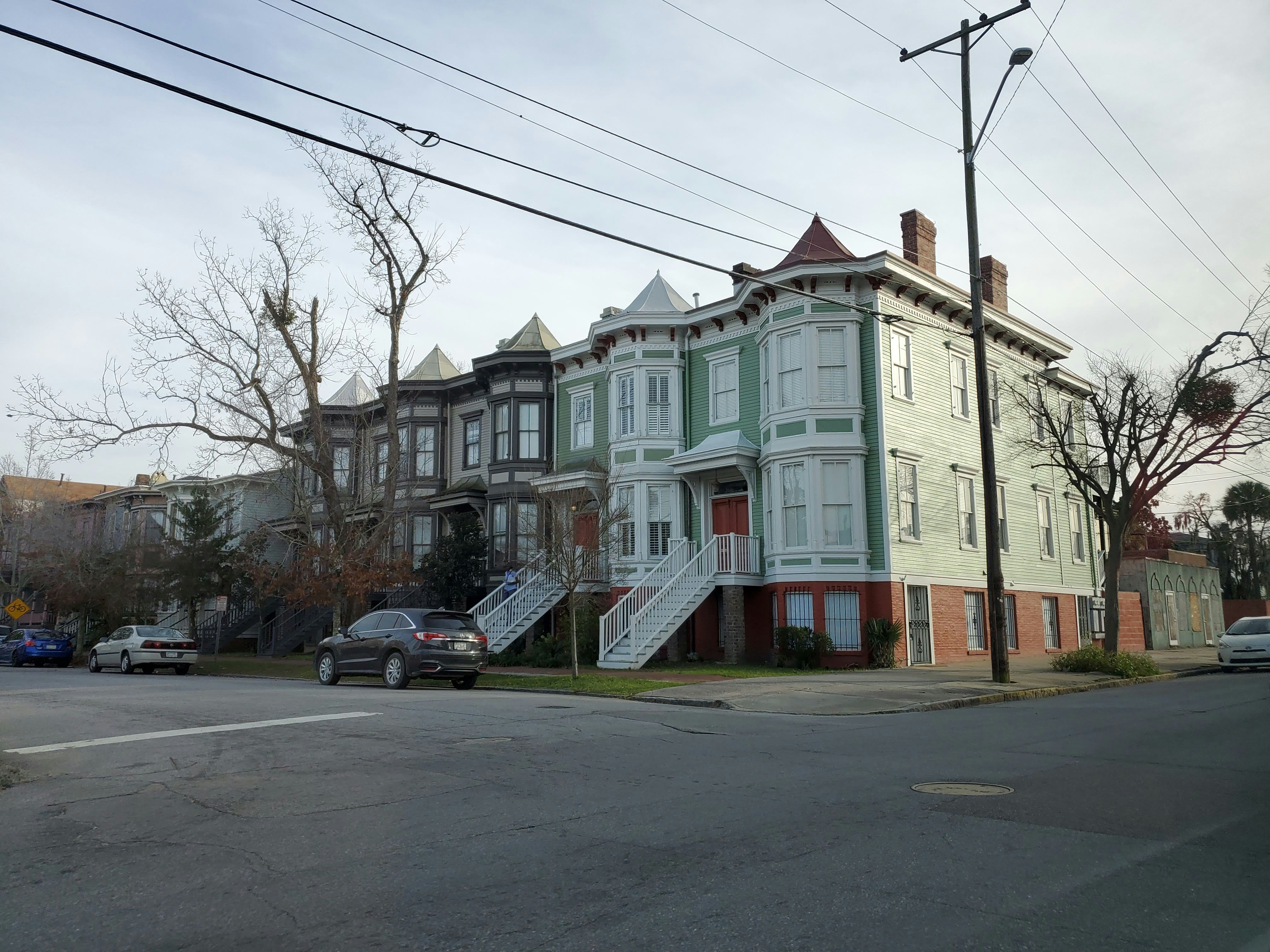 Victorian-style houses with ornate details on a calm street corner during daytime.
