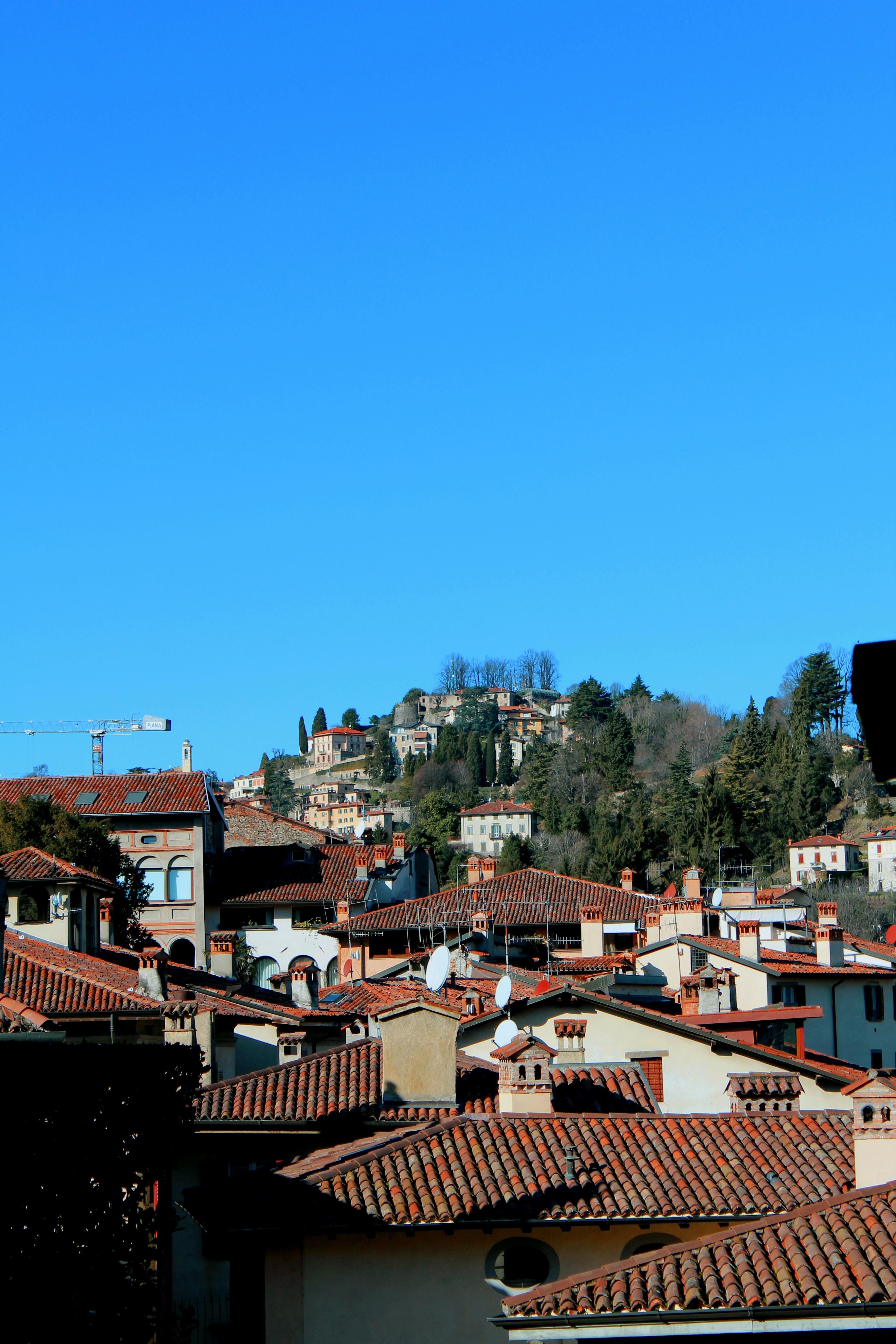 Terracotta rooftops of a hillside town beneath a clear blue sky.