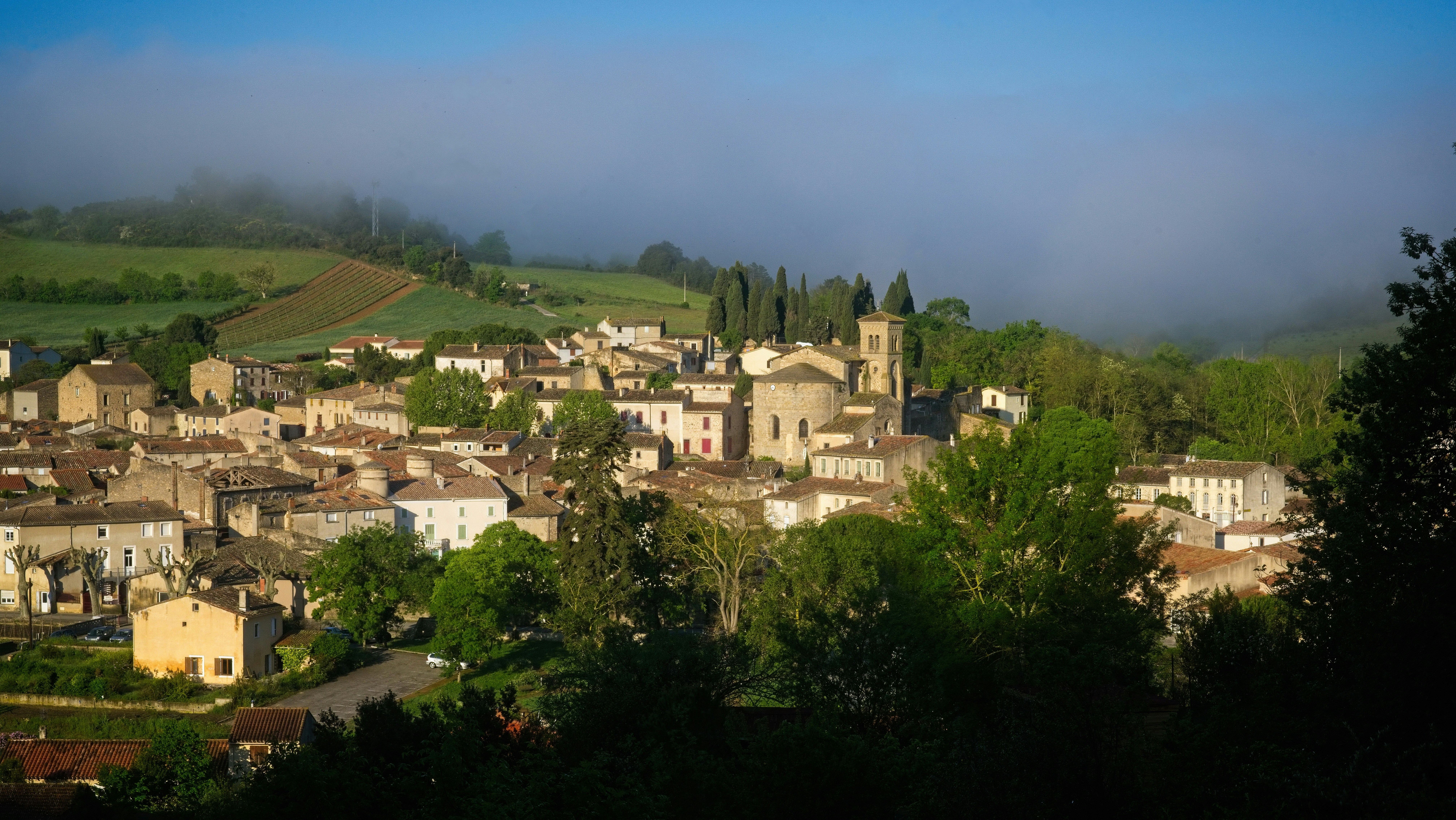 Fog-tinged hillside village crowned by a stone church tower