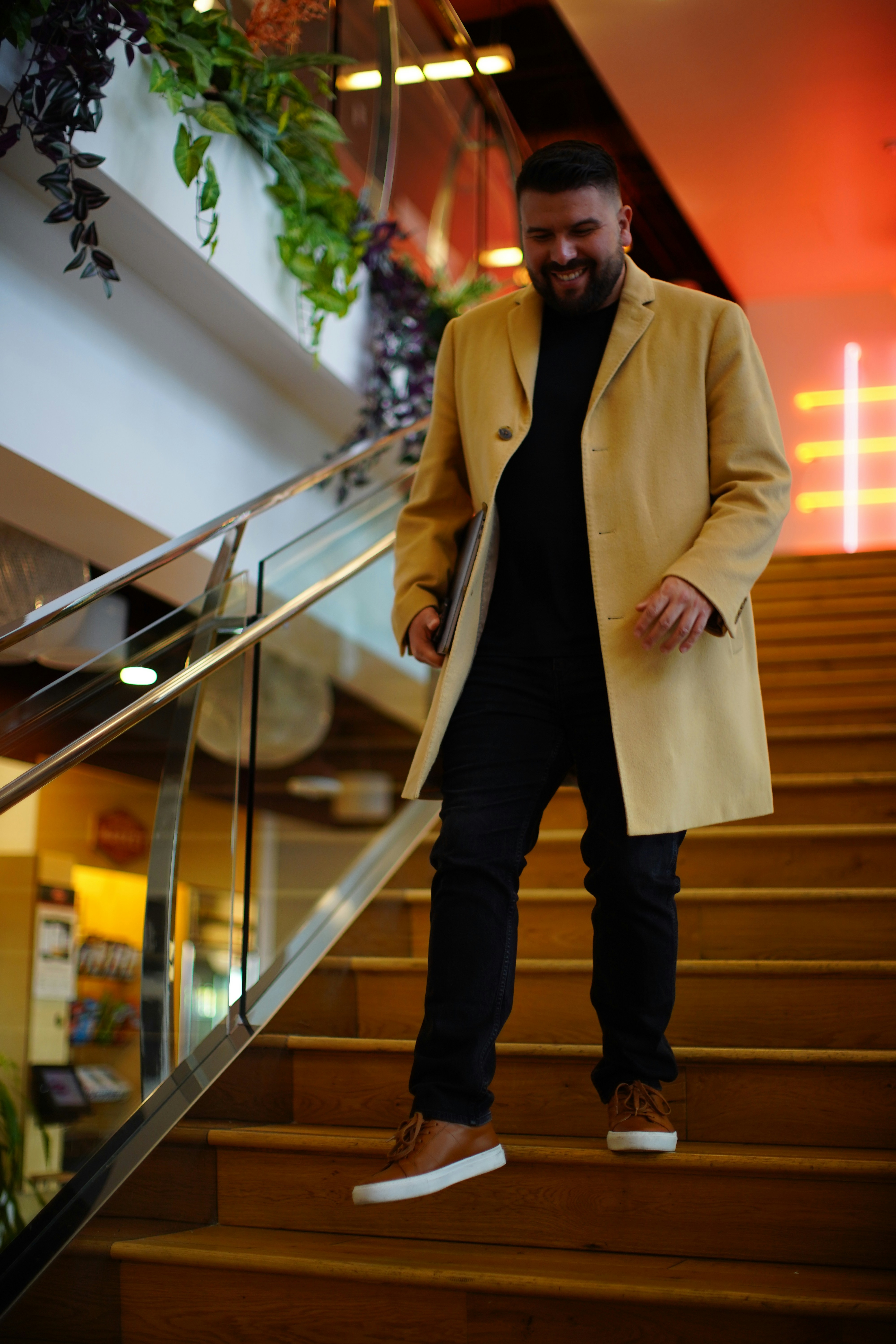 Stepping into Warm Light: A Man in a Camel Coat Descends Neon Stairs