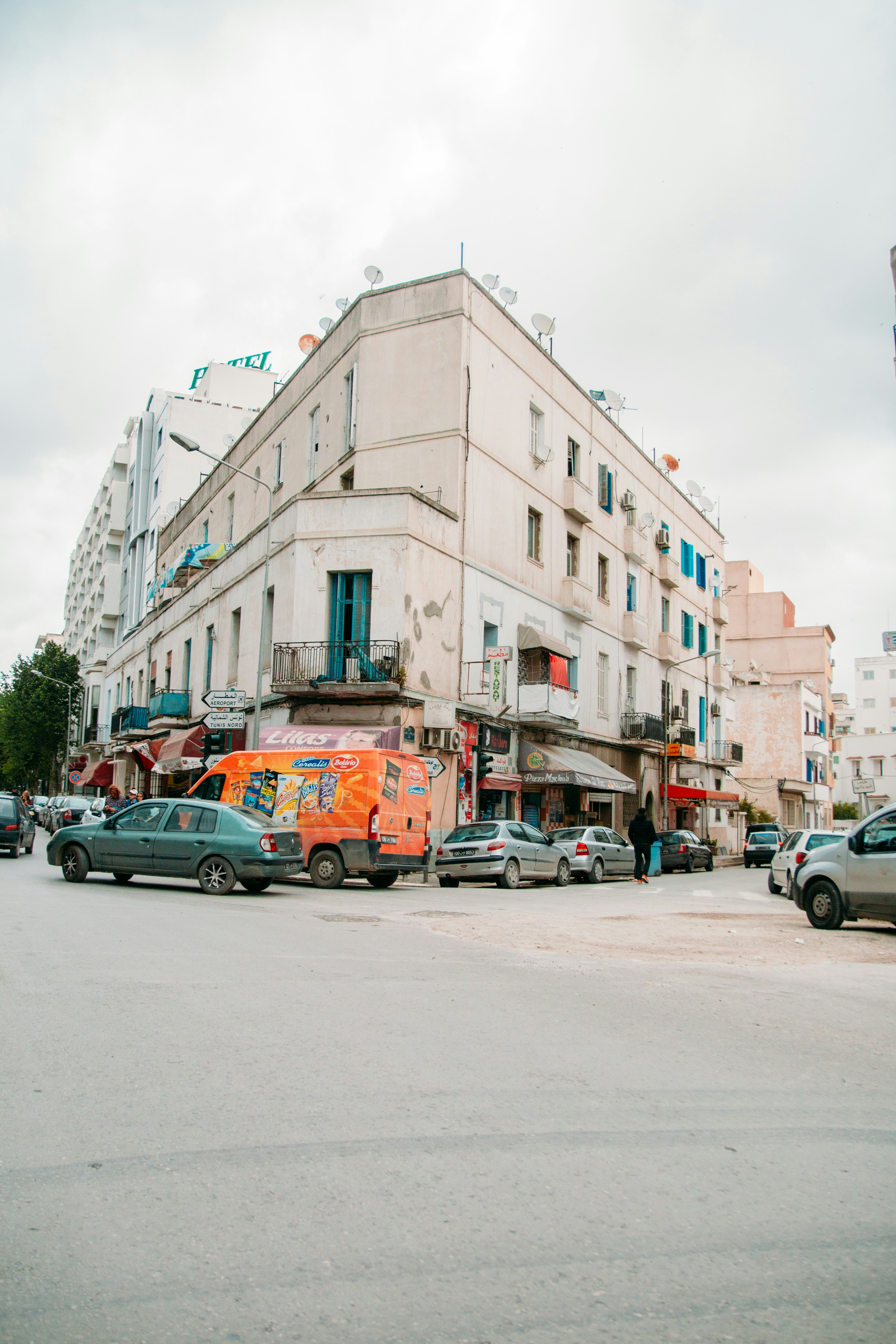 Cornerlight at the Junction: Beige Facades, Blue Accents, and an Orange Delivery Van