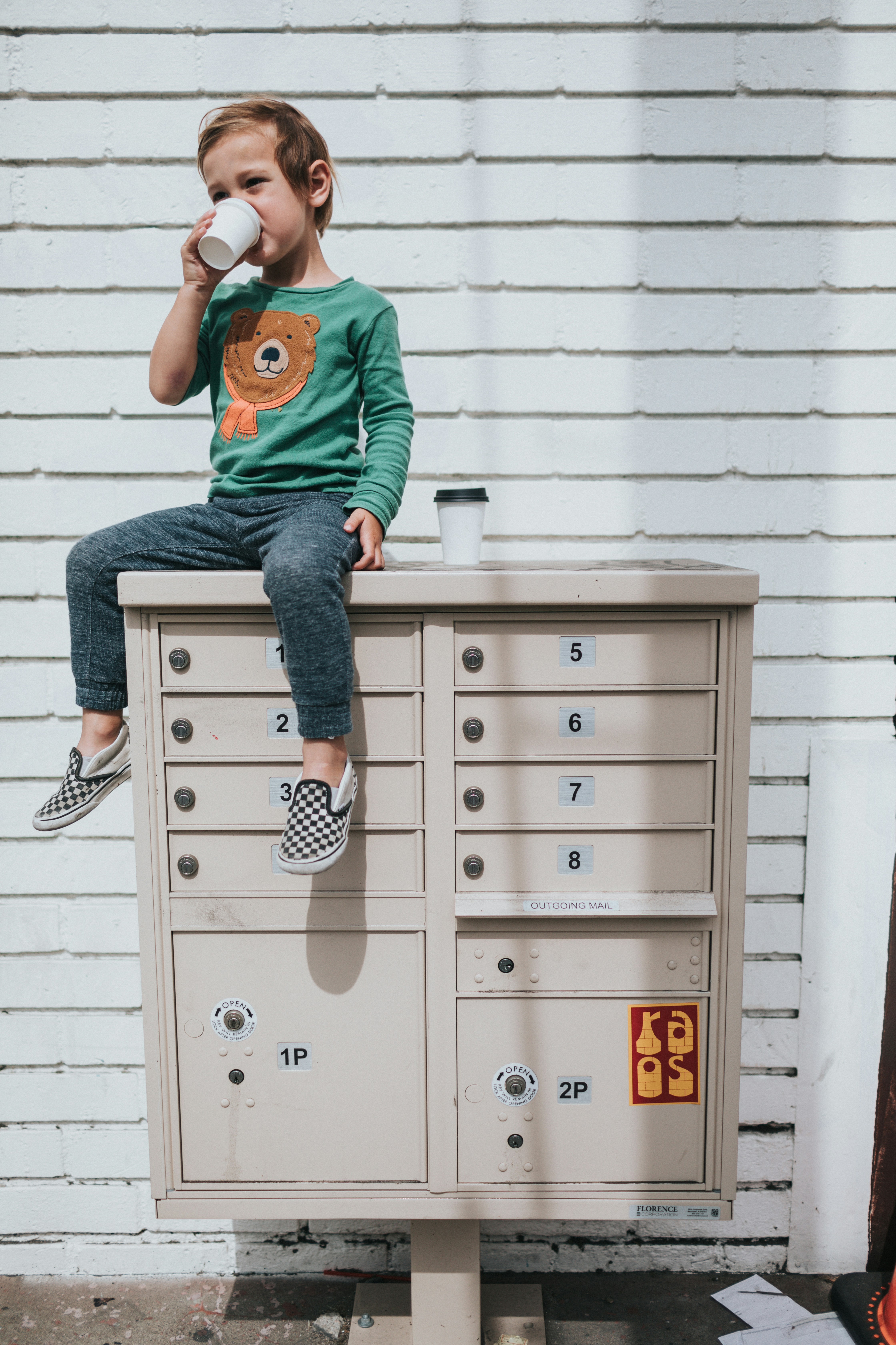 Morning Pause on a Mailbox Stack: A Kid Sips in Daylight
