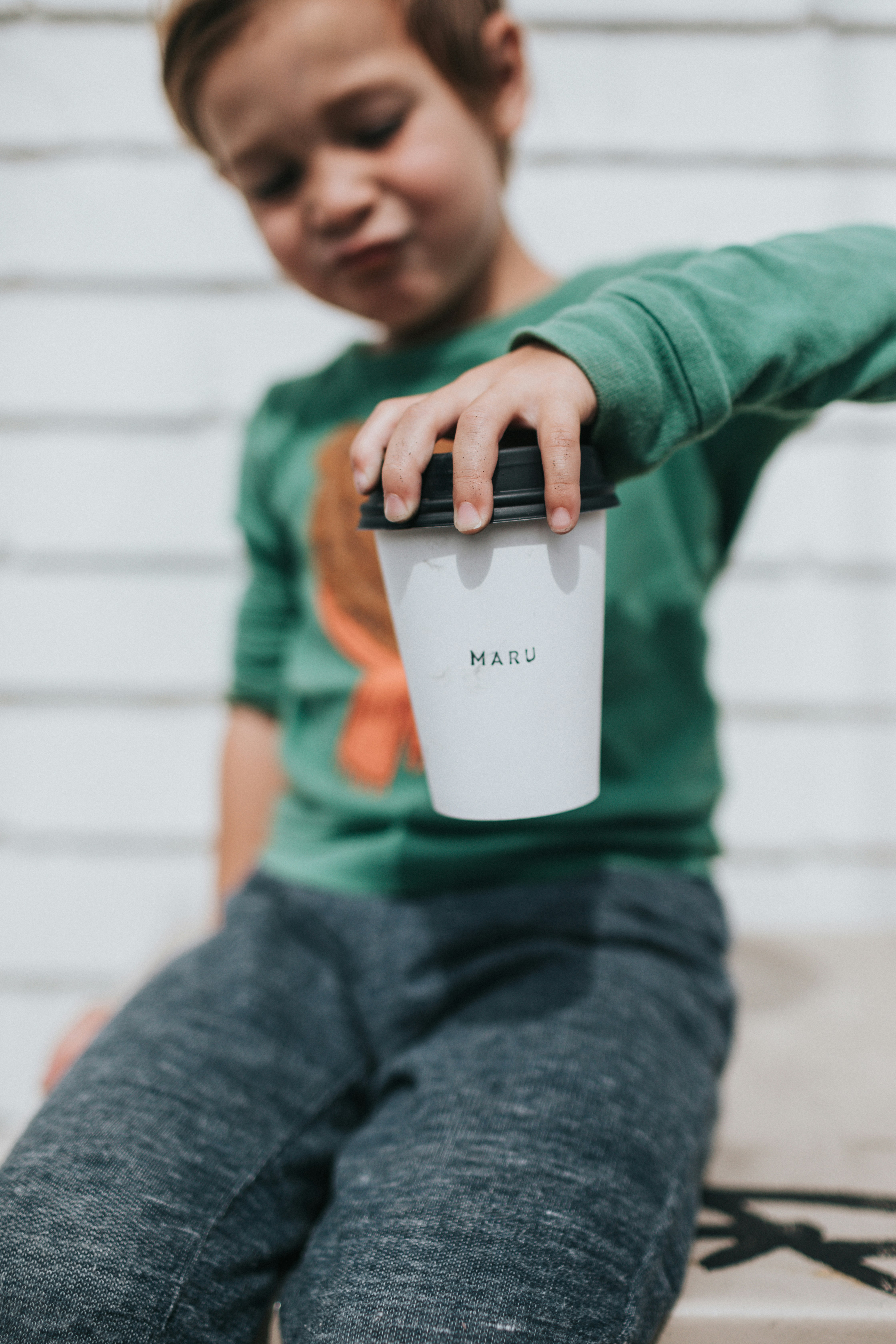 Coffee Cup Confusion: A Child Reaches Forward with a Humble Startup Drink