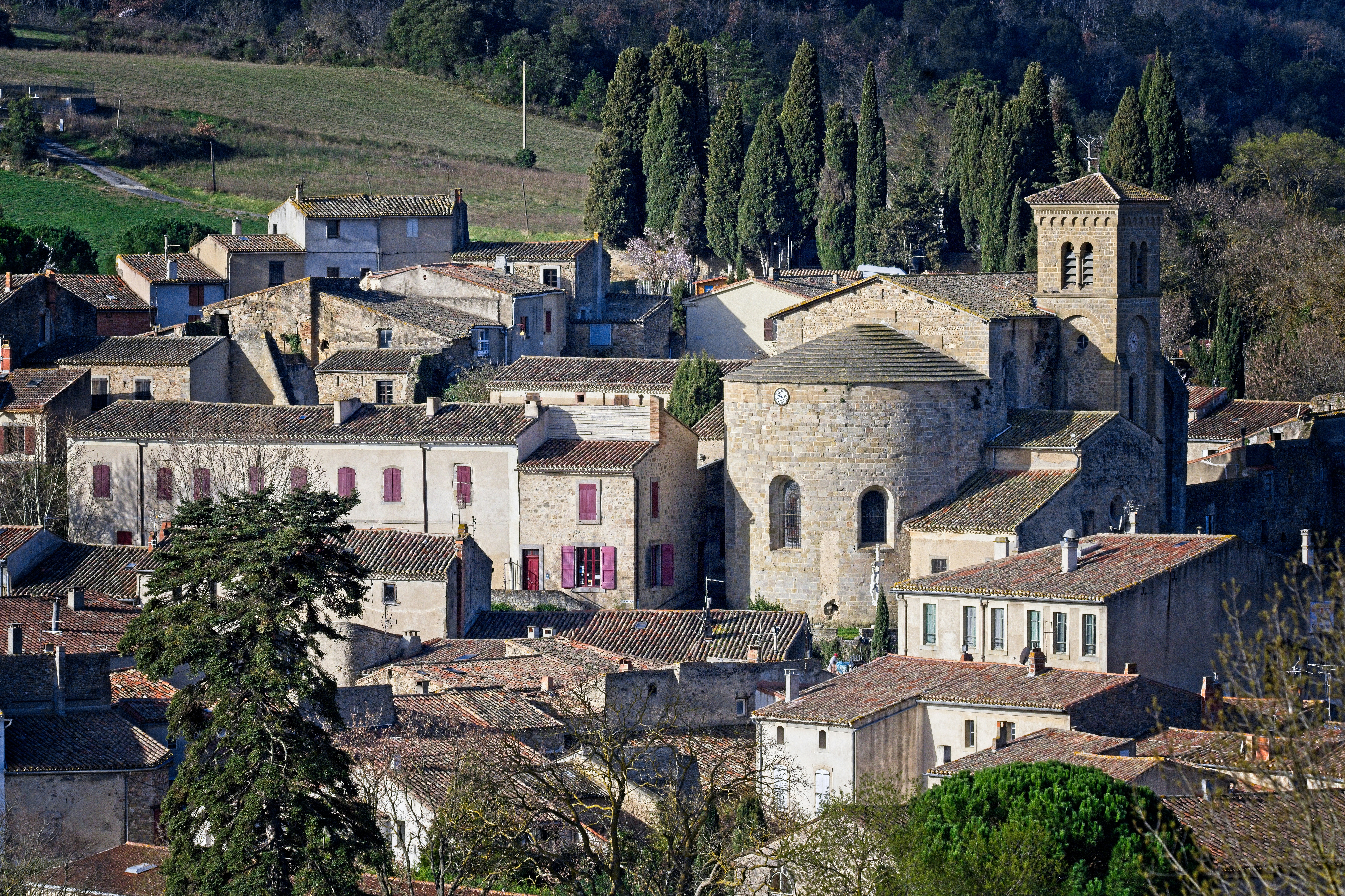 Historic village scene featuring stone buildings and a prominent church, surrounded by lush greenery. The architecture reflects the charm of bygone eras.