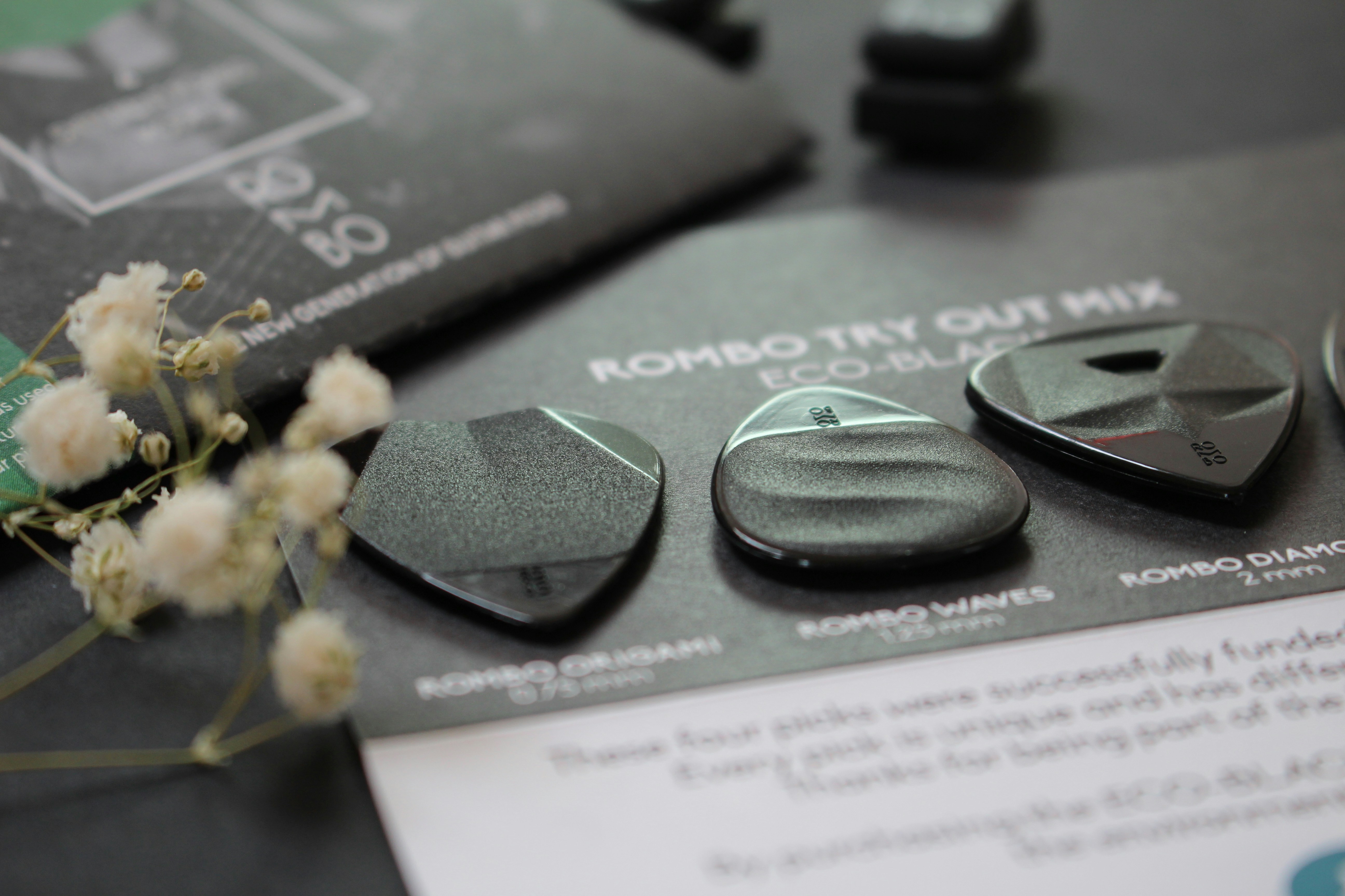 Close-up of a guitar pick display with soft-focus flowers
