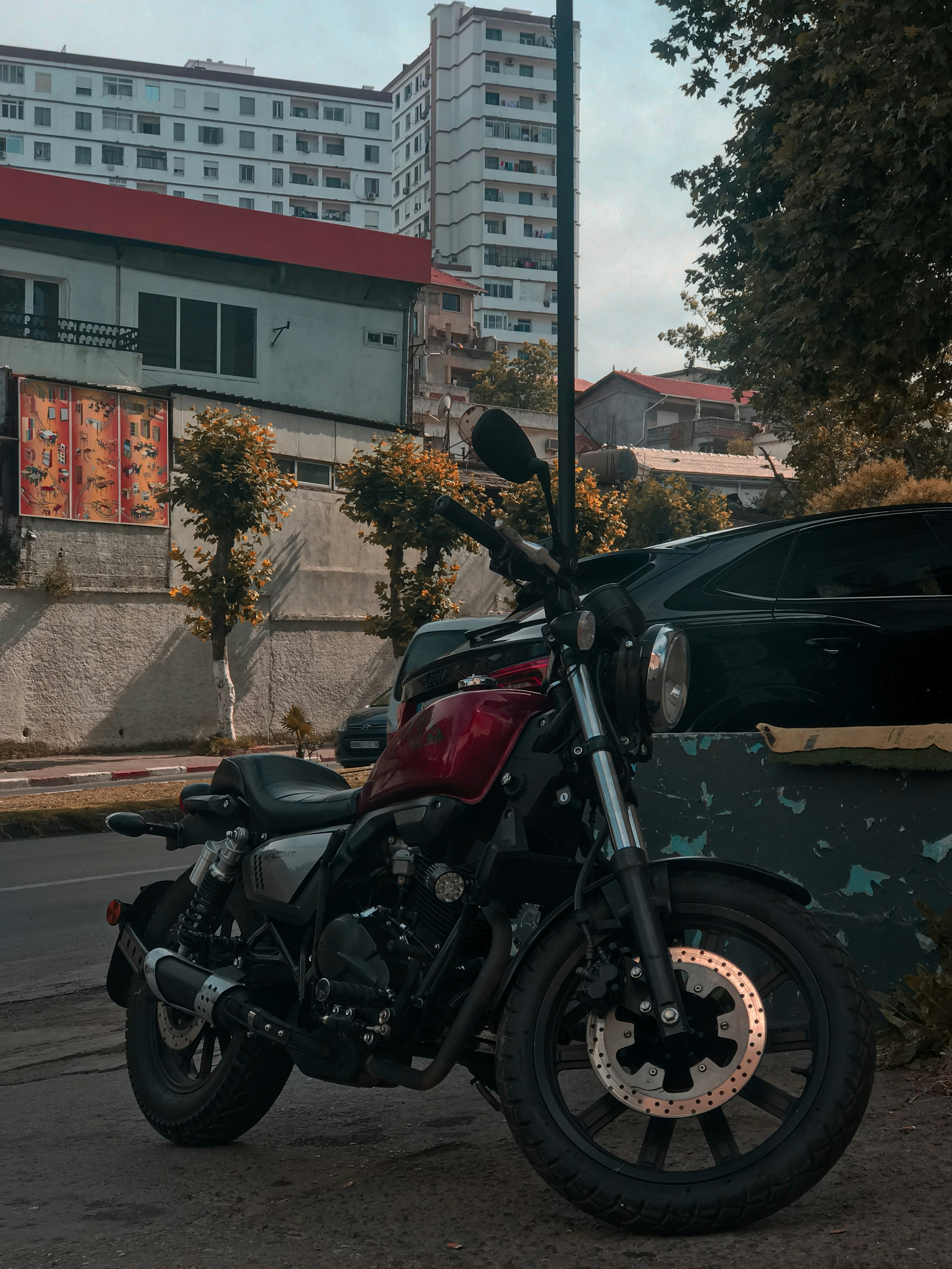 black and red motorcycle parked beside black suv during daytime