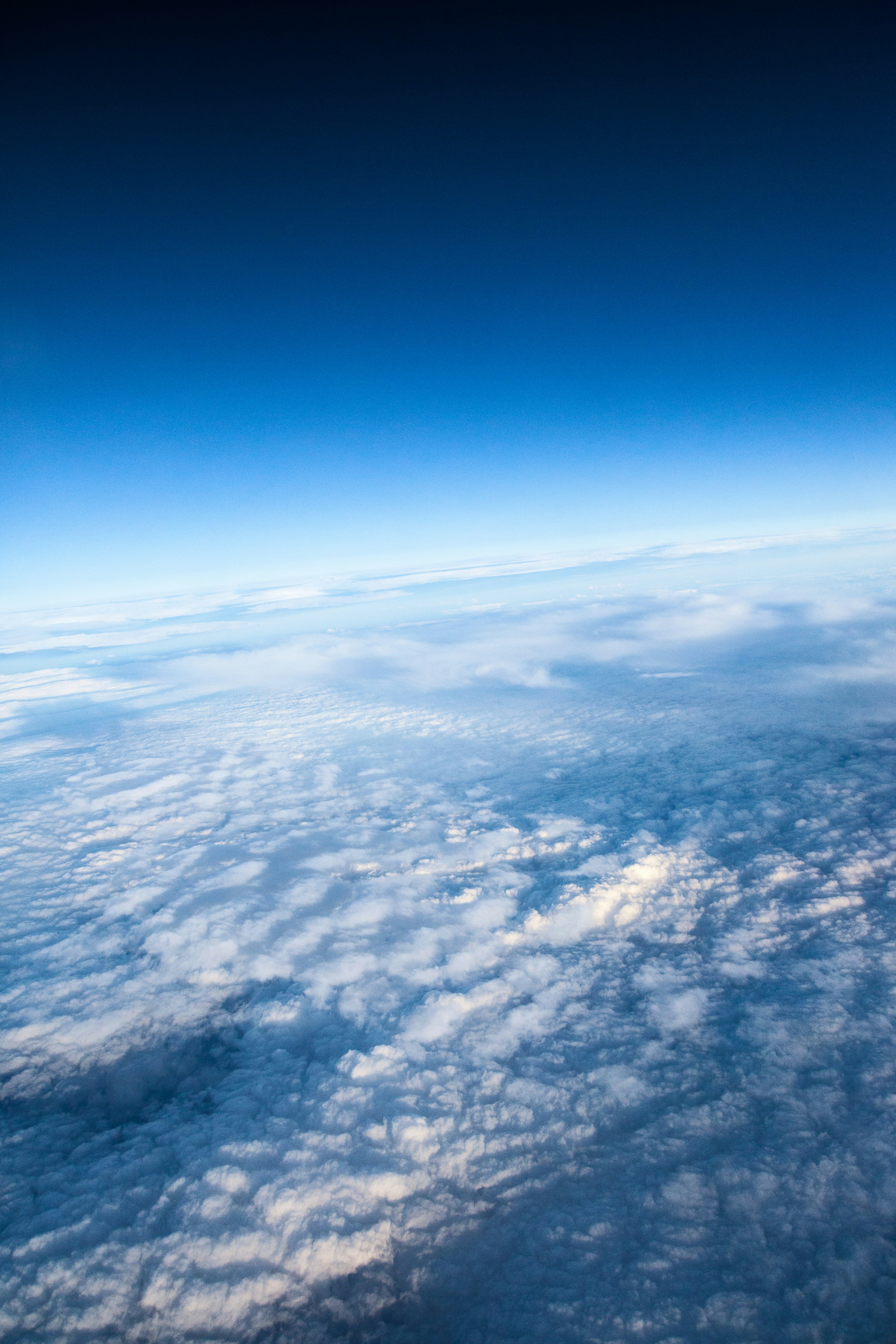 Expansive cloudscape viewed from high altitude beneath a deep blue sky.