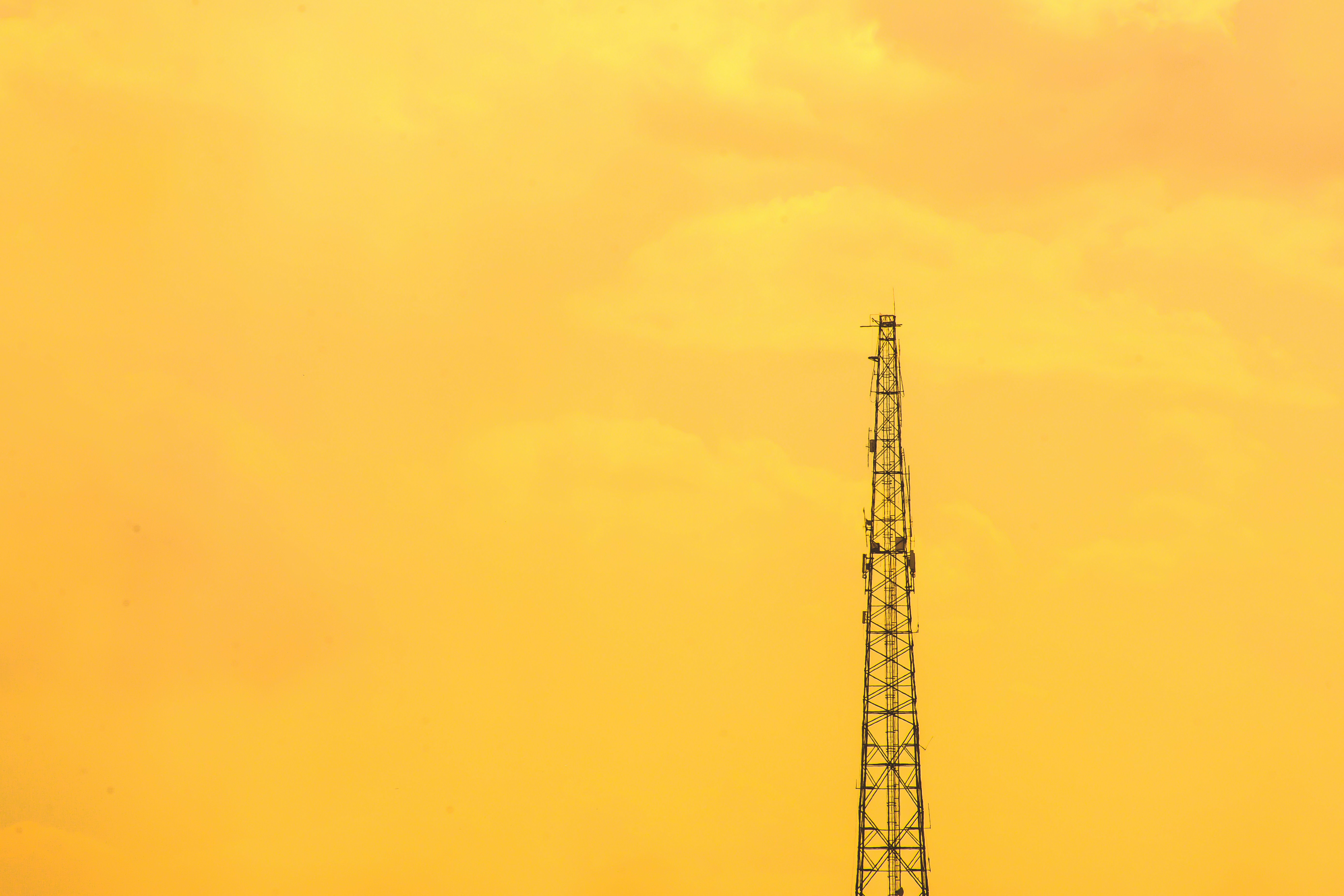 A tall communication tower silhouetted against a golden-hued sky, capturing the essence of technology meeting nature.