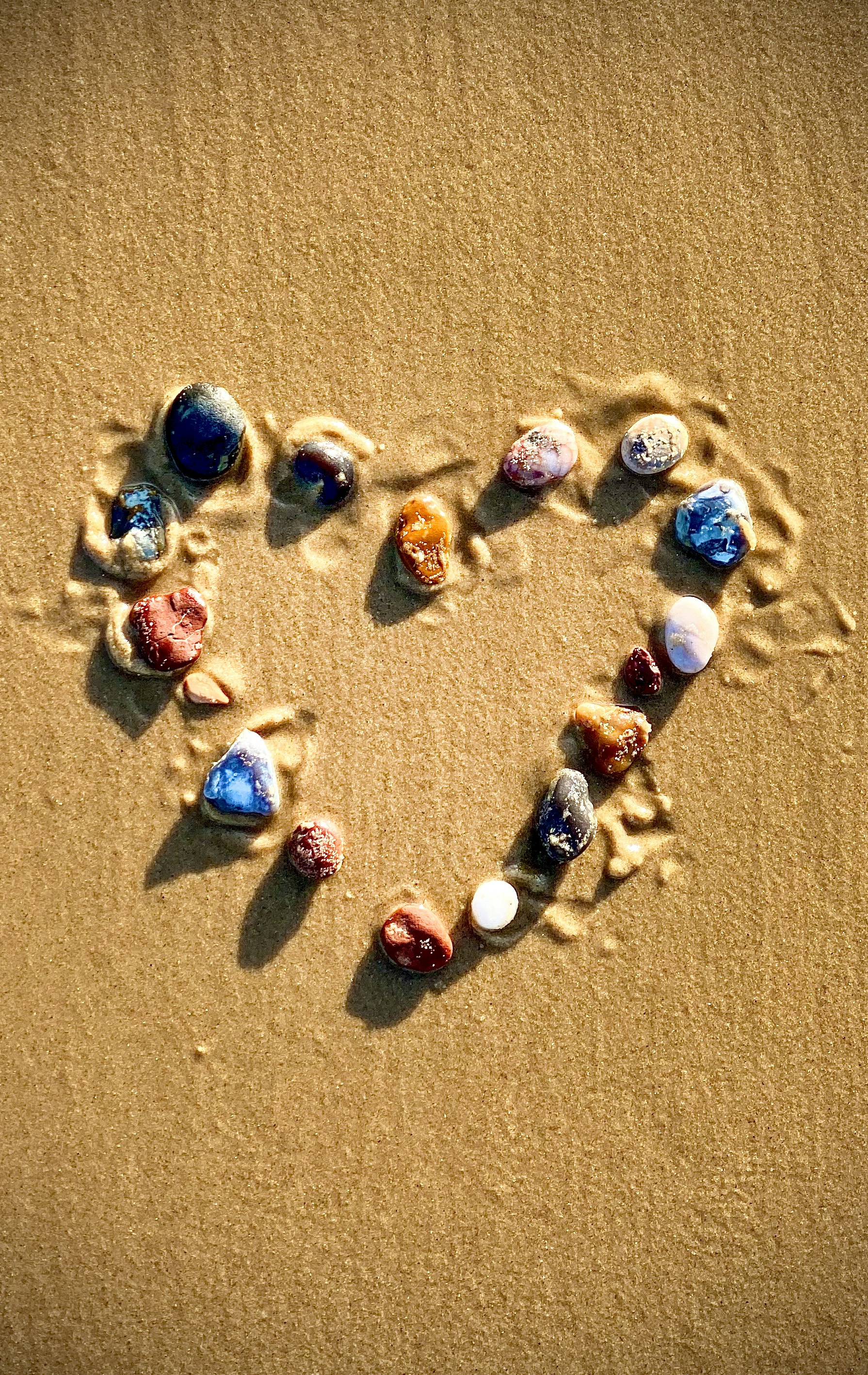 Heart of coloured pebbles on the sandy beach at Southwold