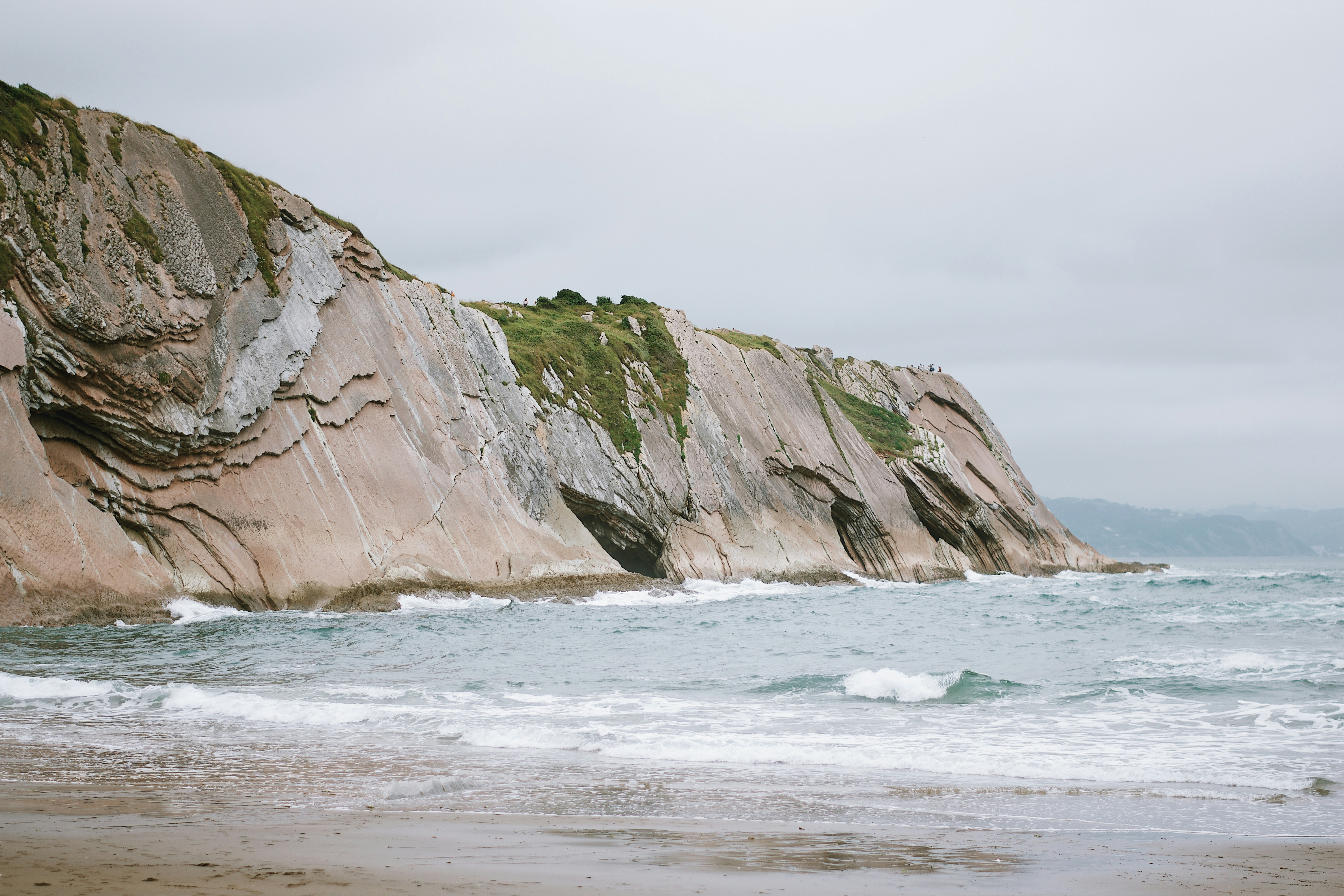 Edge of Stone: Cliff Face and Quiet Sea under Gray Skies