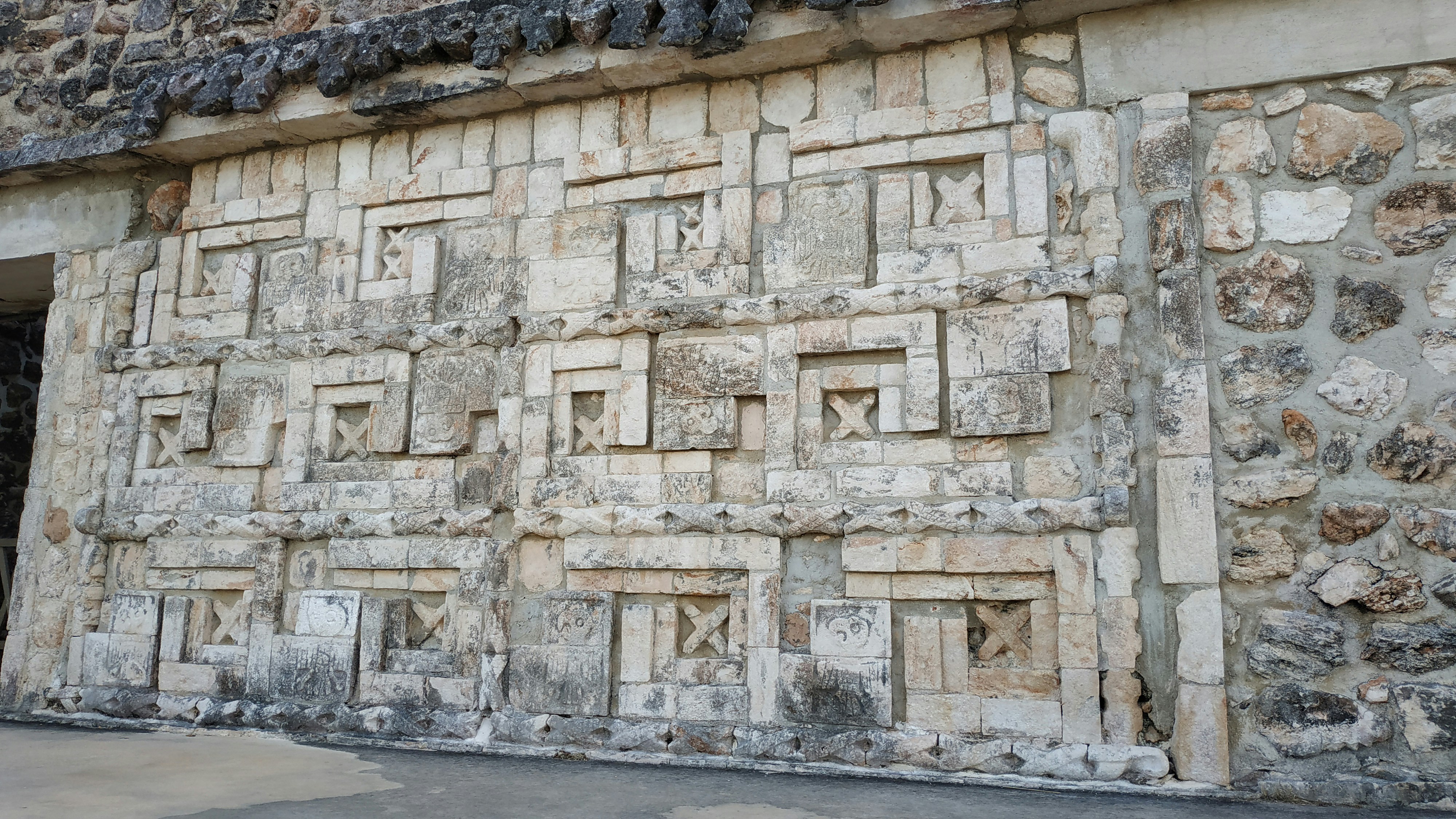 Detailed stone wall with geometric carvings at Mayan ruins in Uxmal.