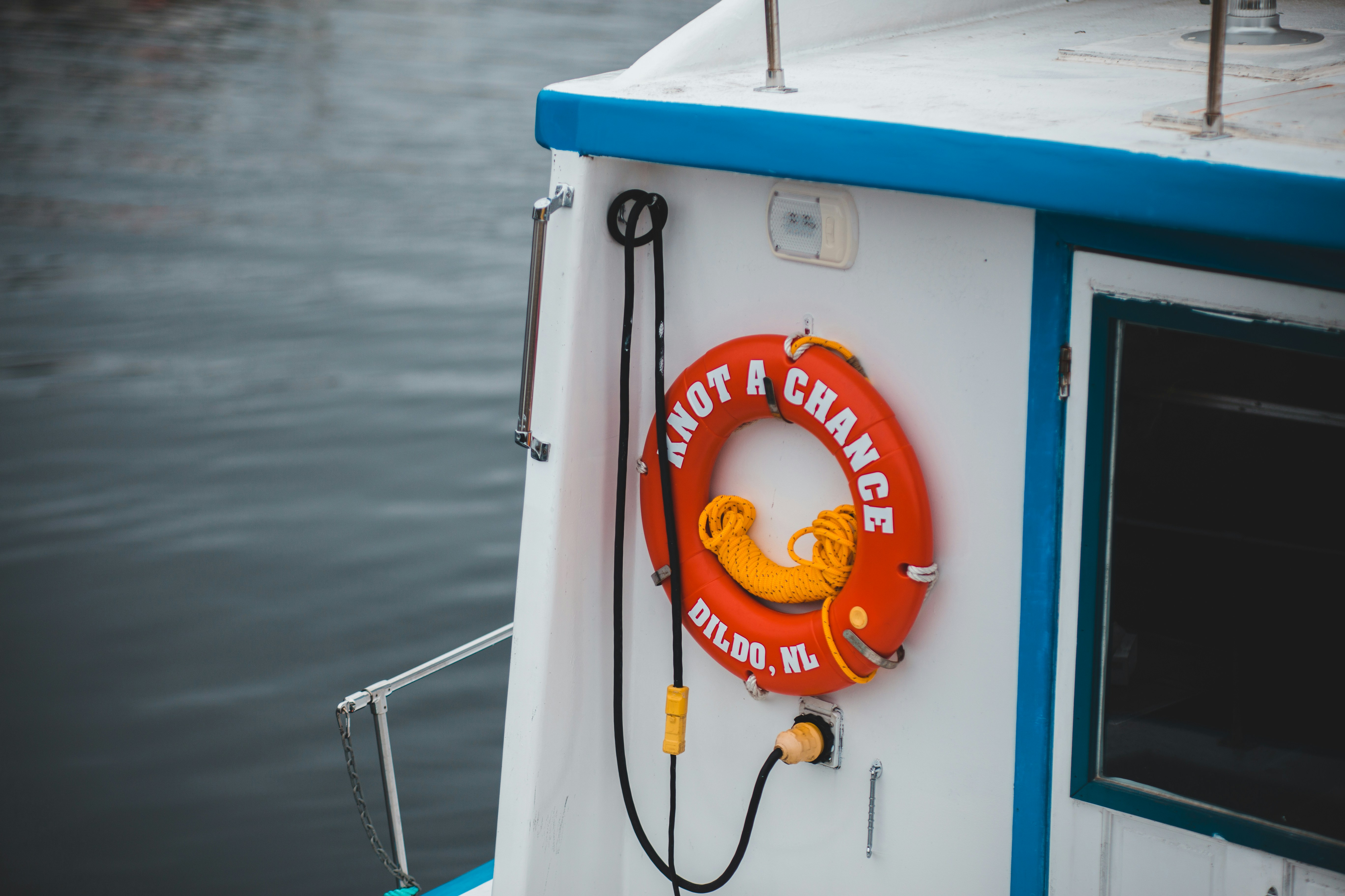 Orange Lifebuoy on a White Boat with Blue Trim by Quiet Water