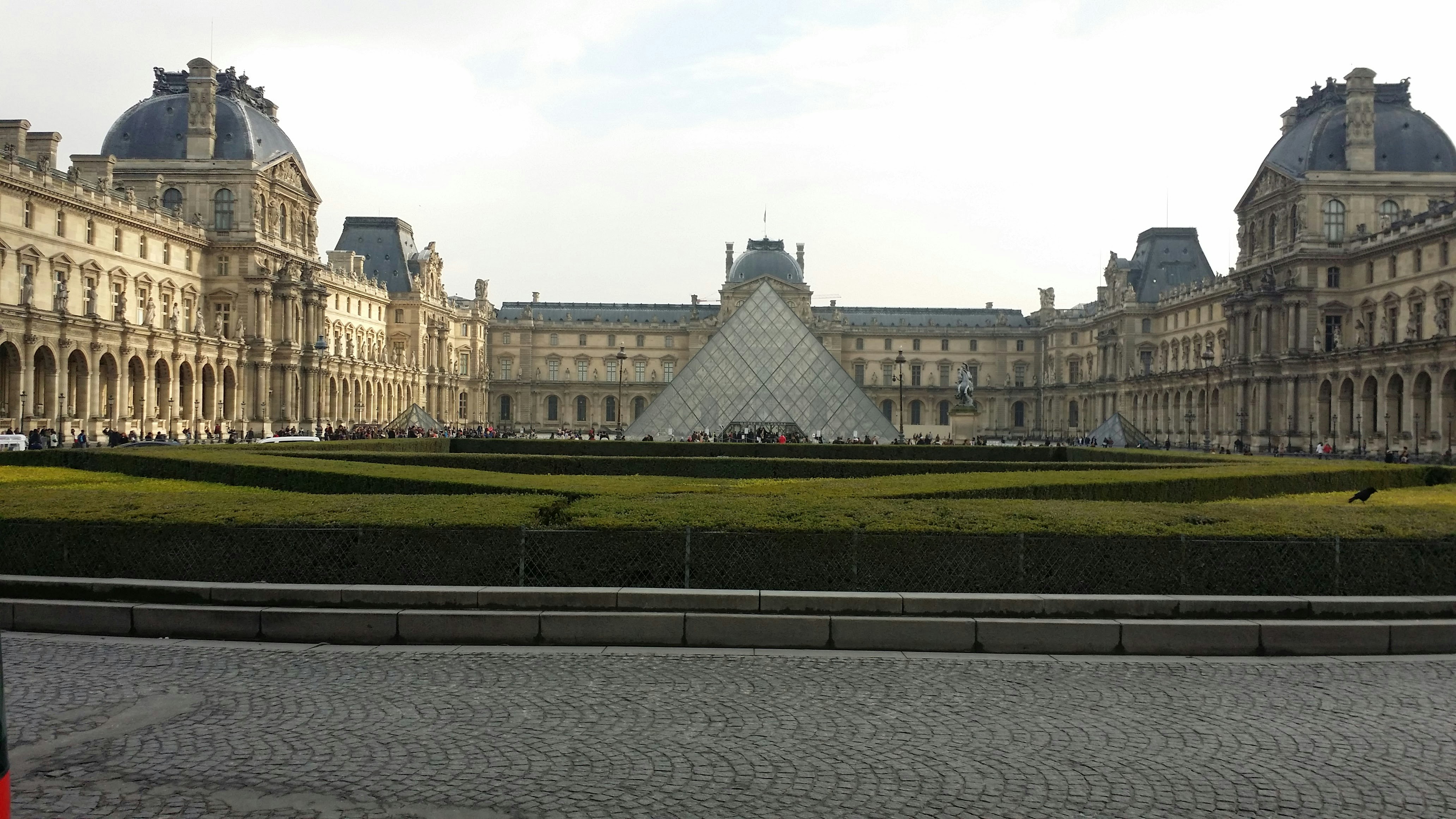 The iconic glass pyramid stands prominently in the courtyard of the Louvre, framed by classical architecture and manicured gardens.