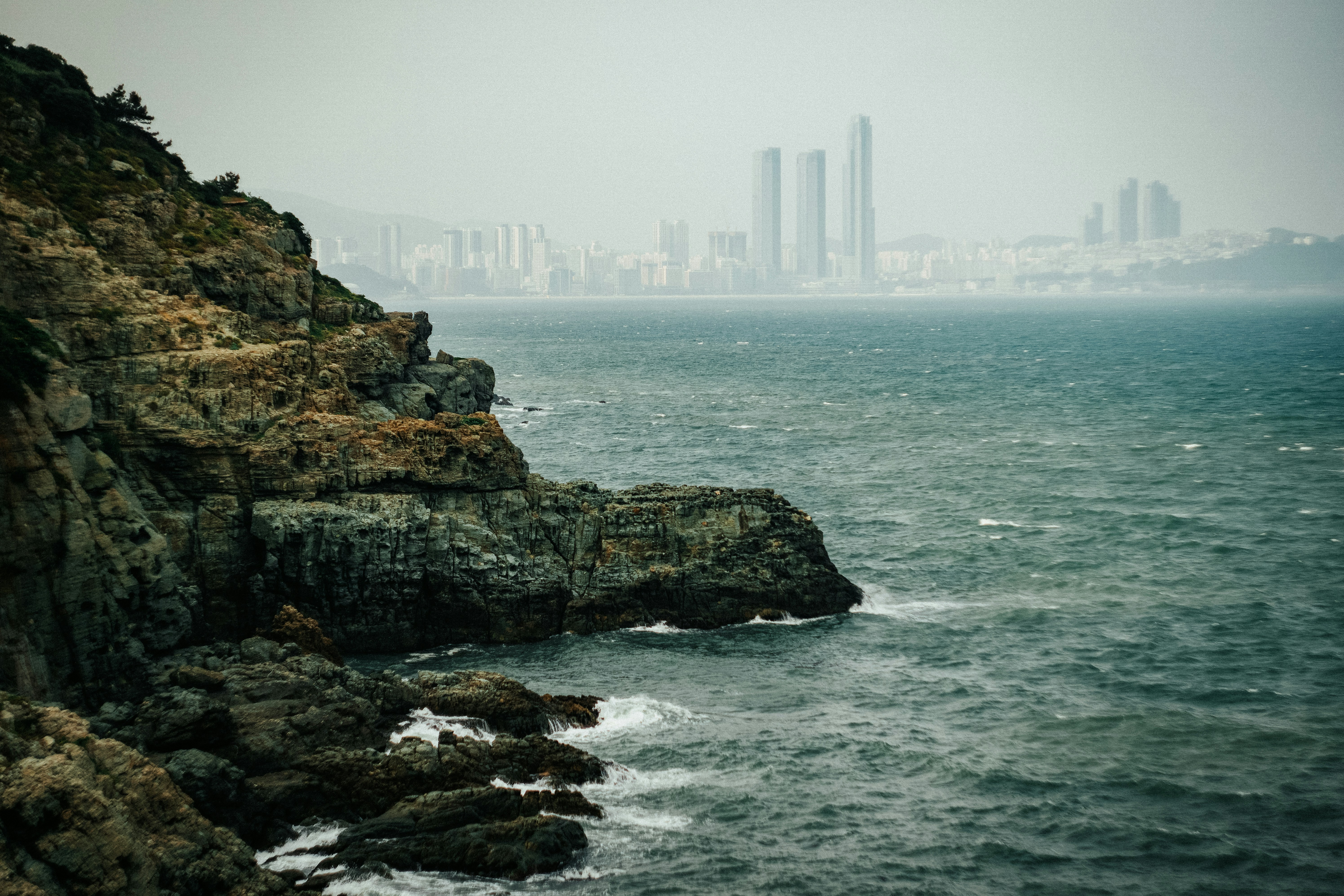 High rise building on rock formation near sea during daytime photo ...