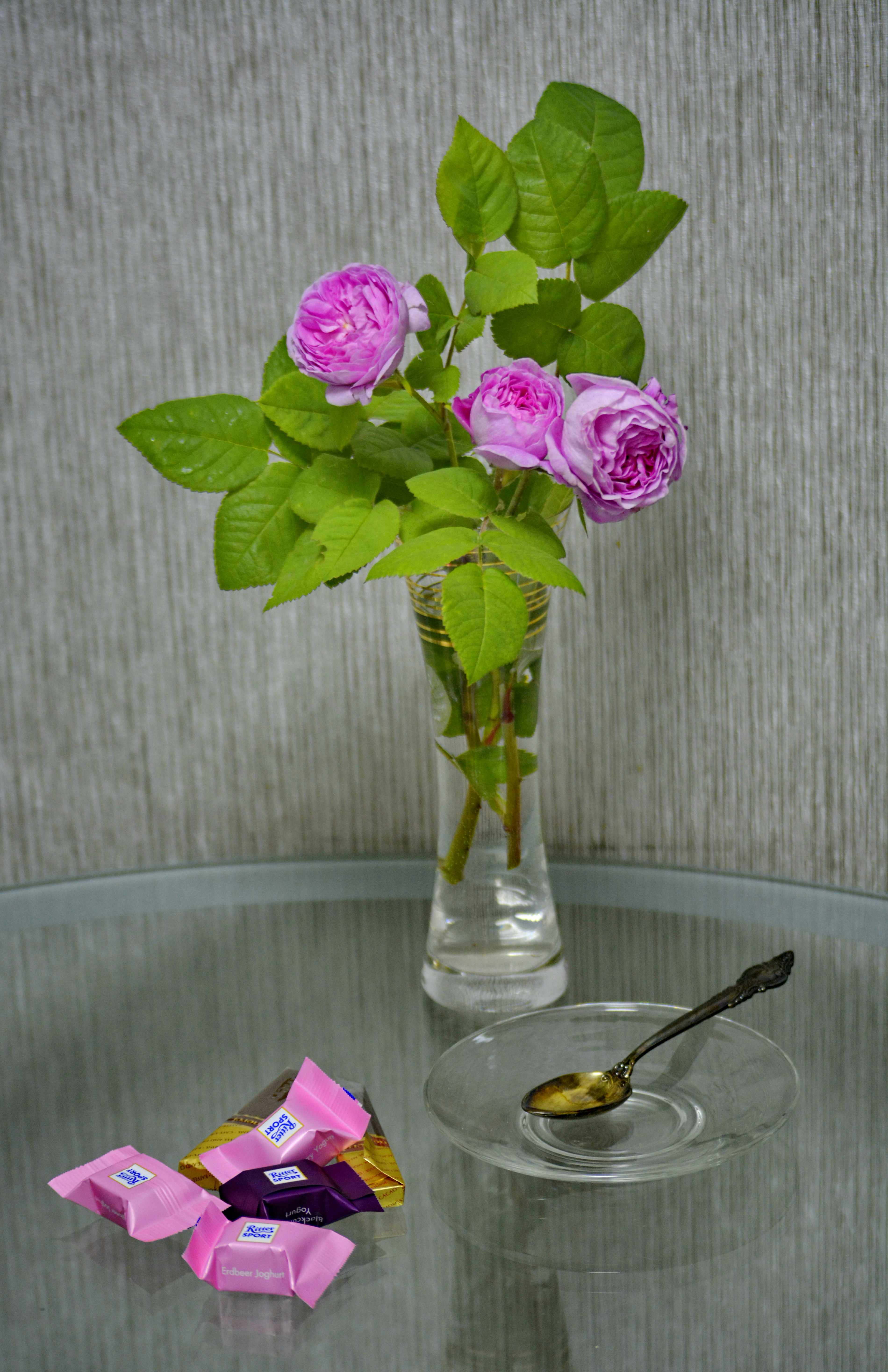 
Evening bouquet. Bouquet of pink roses in a vase on a glass table.
A teaspoon lies on a glass saucer. A glass vase is reflected in a glass table. Soft light.
Nearby are some sweets in brightly colored wrappers. A romantic evening with a mistress - guaranteed!