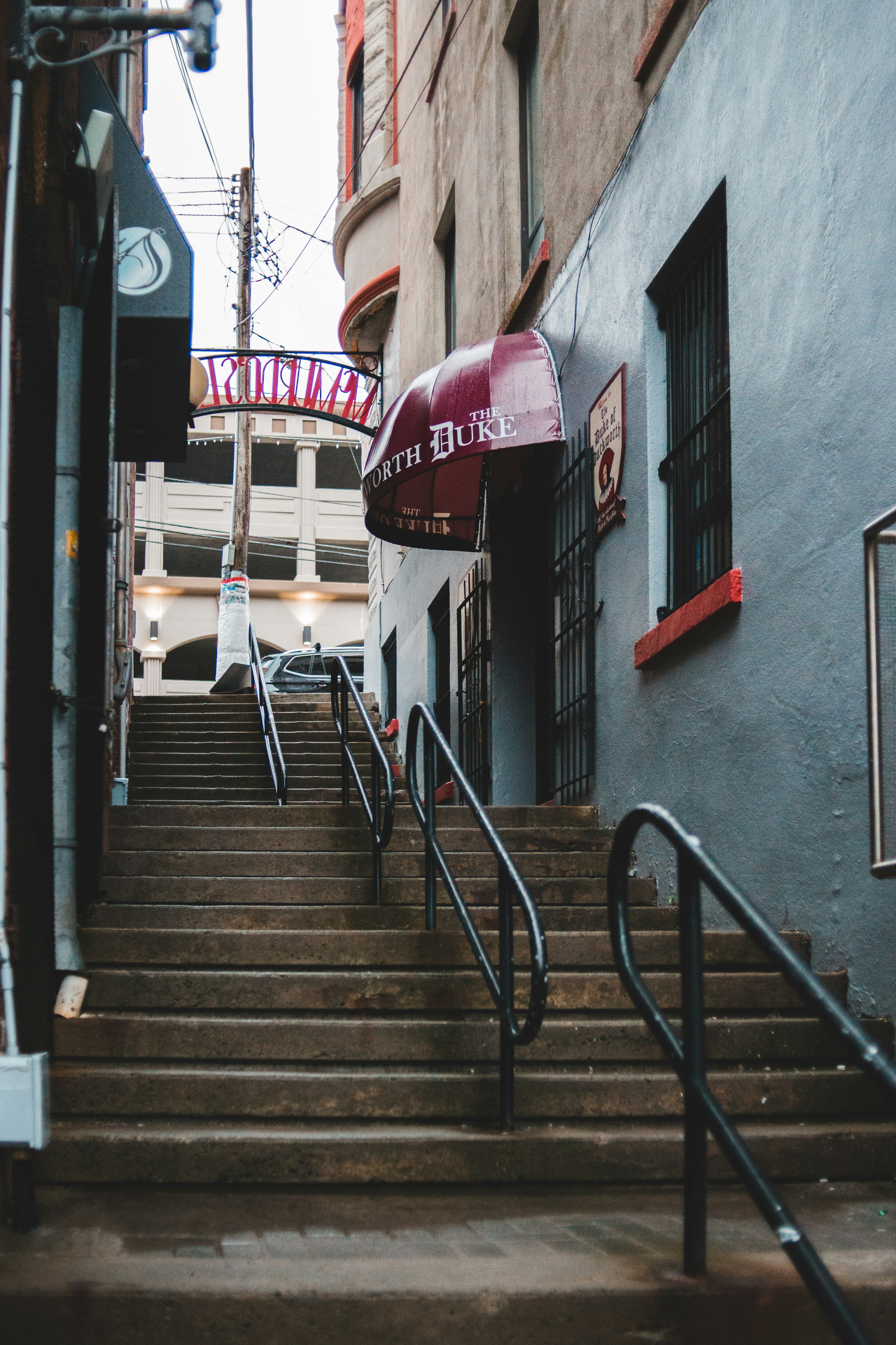 Staircase to the Neon Moon: Alleyway ascent toward the cafe awning