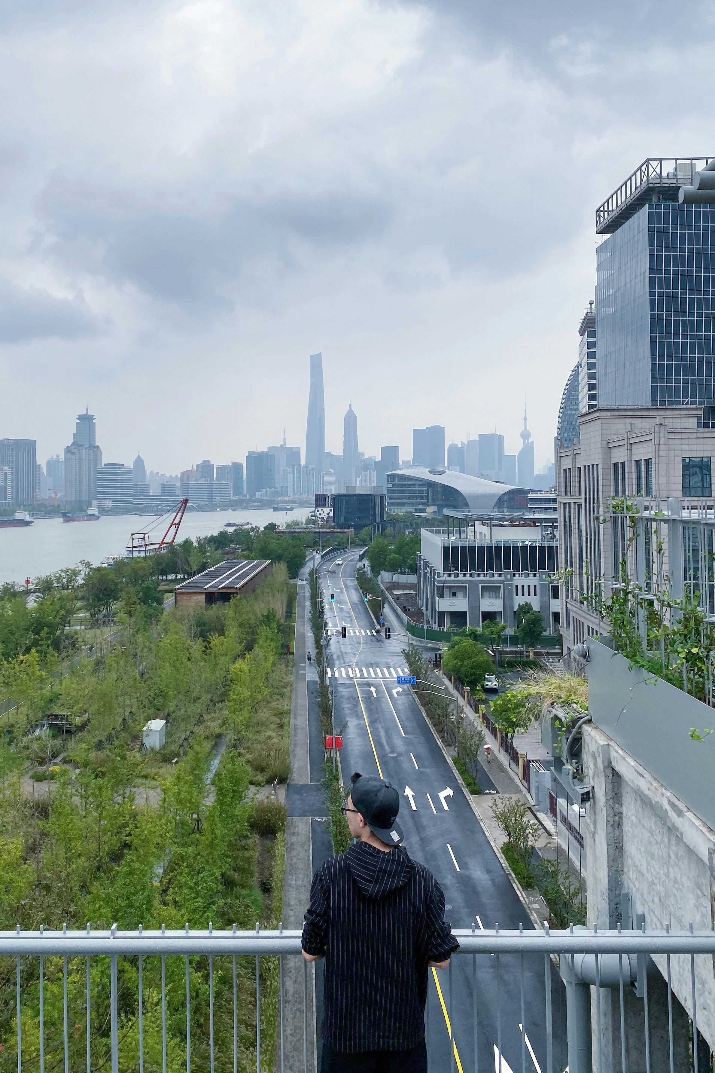 Railing Over the River: A Figure Gazing Toward the City's Glass Horizon