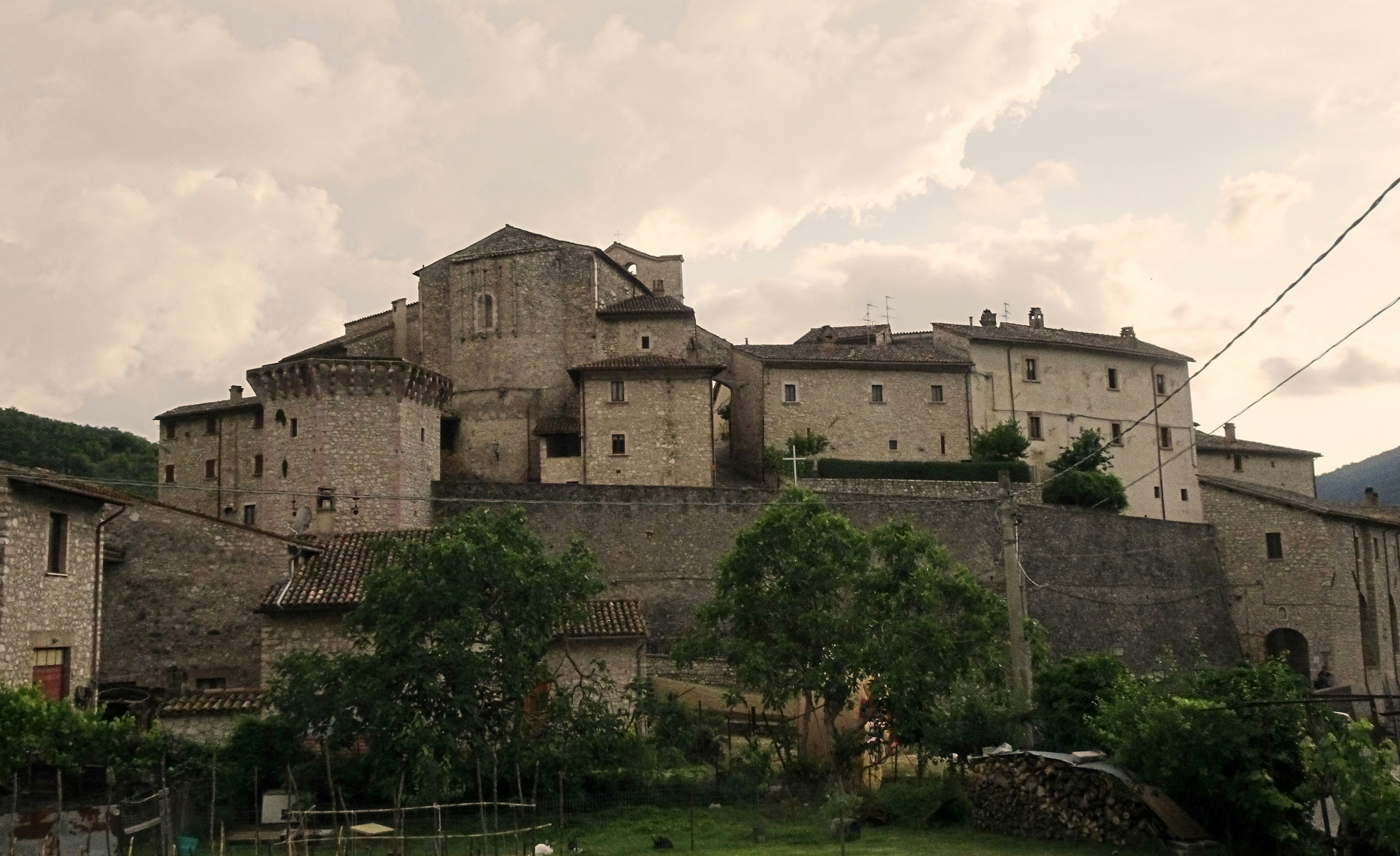 Historic stone fortress surrounded by lush greenery beneath a cloud-dotted sky.