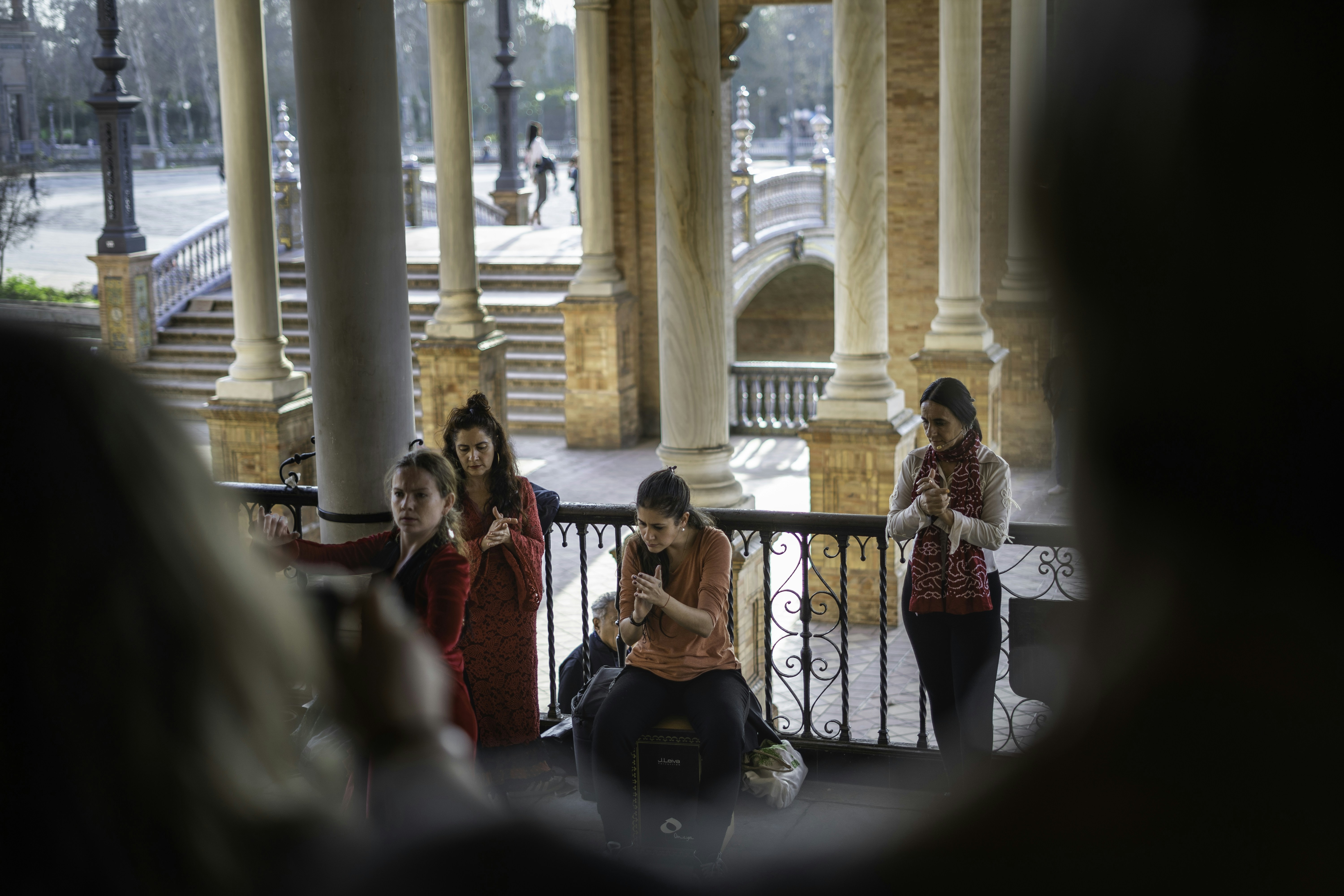 Flamenco dancer and musicians perform under ornate arches in Seville's iconic square.