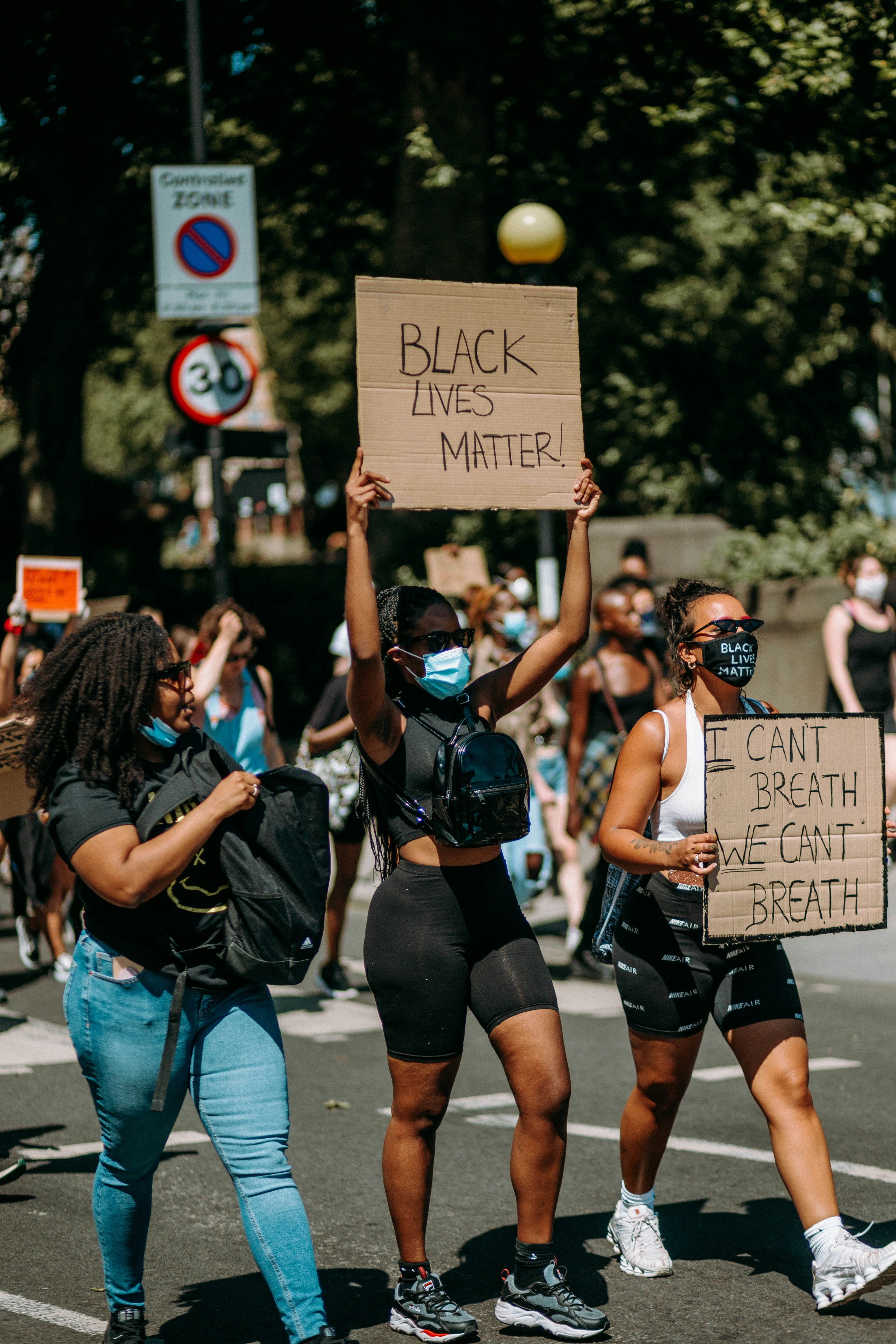 Protesters holding signs advocating for racial justice during a daytime march.
