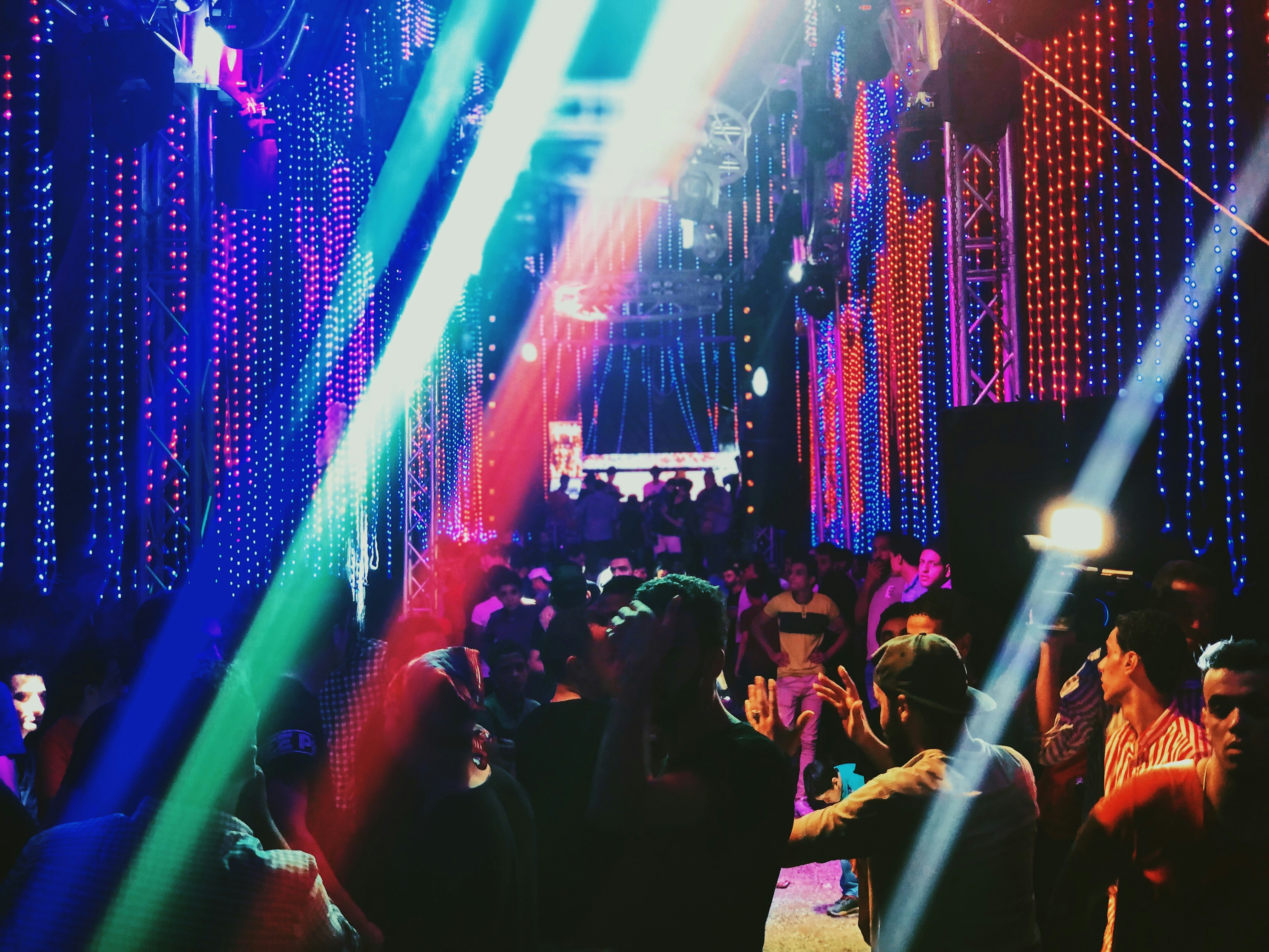 Colorful beams of light illuminate a crowded dance floor at a celebration.