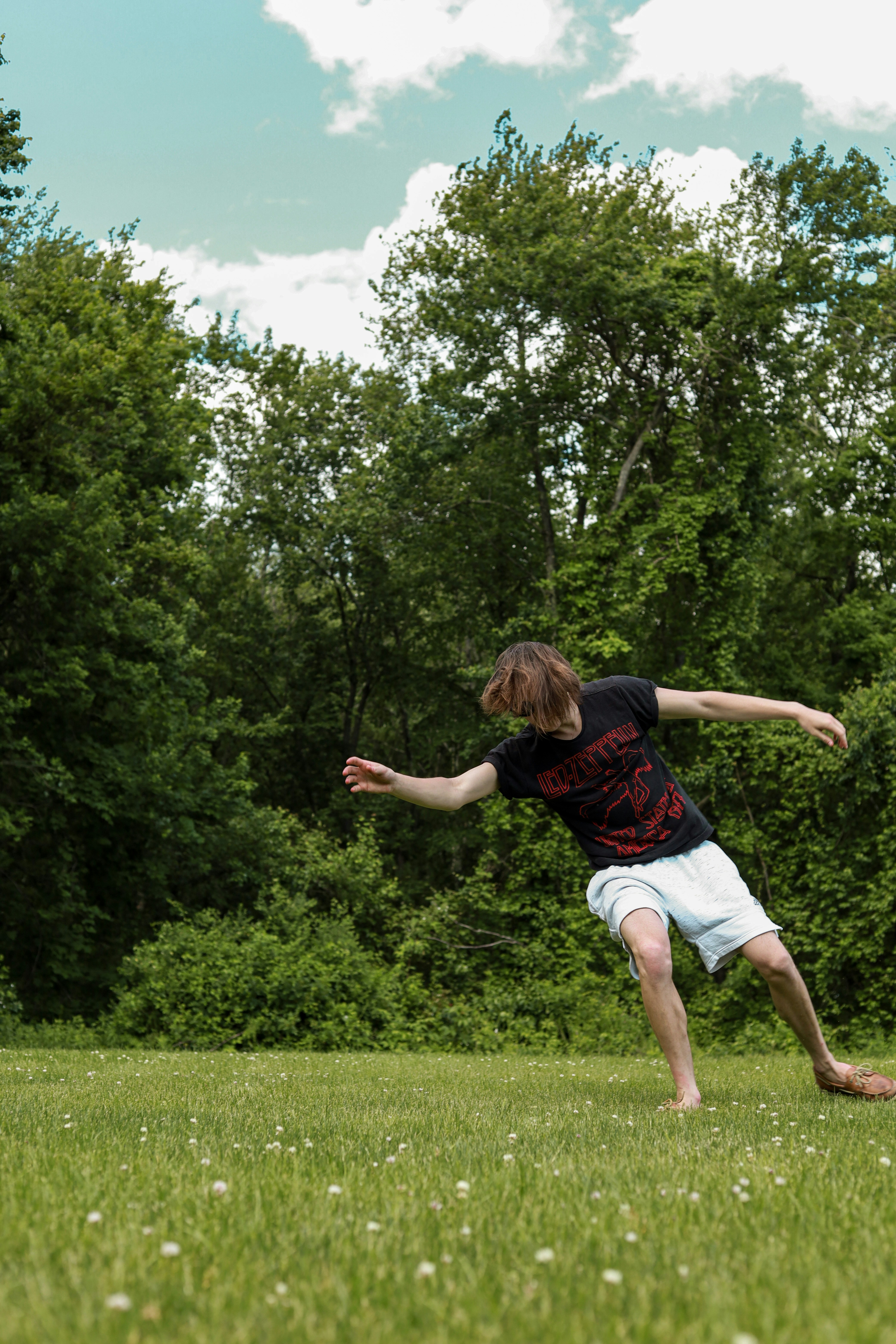 Girl in black t-shirt and white shorts jumping on green grass field ...