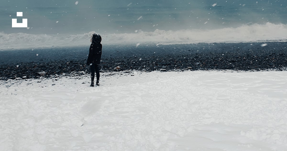 낮 동안 푸른 하늘 아래 눈 덮인 땅에 서 있는 검은 재킷을 입은 사람 사진 Unsplash의 무료 회색 이미지