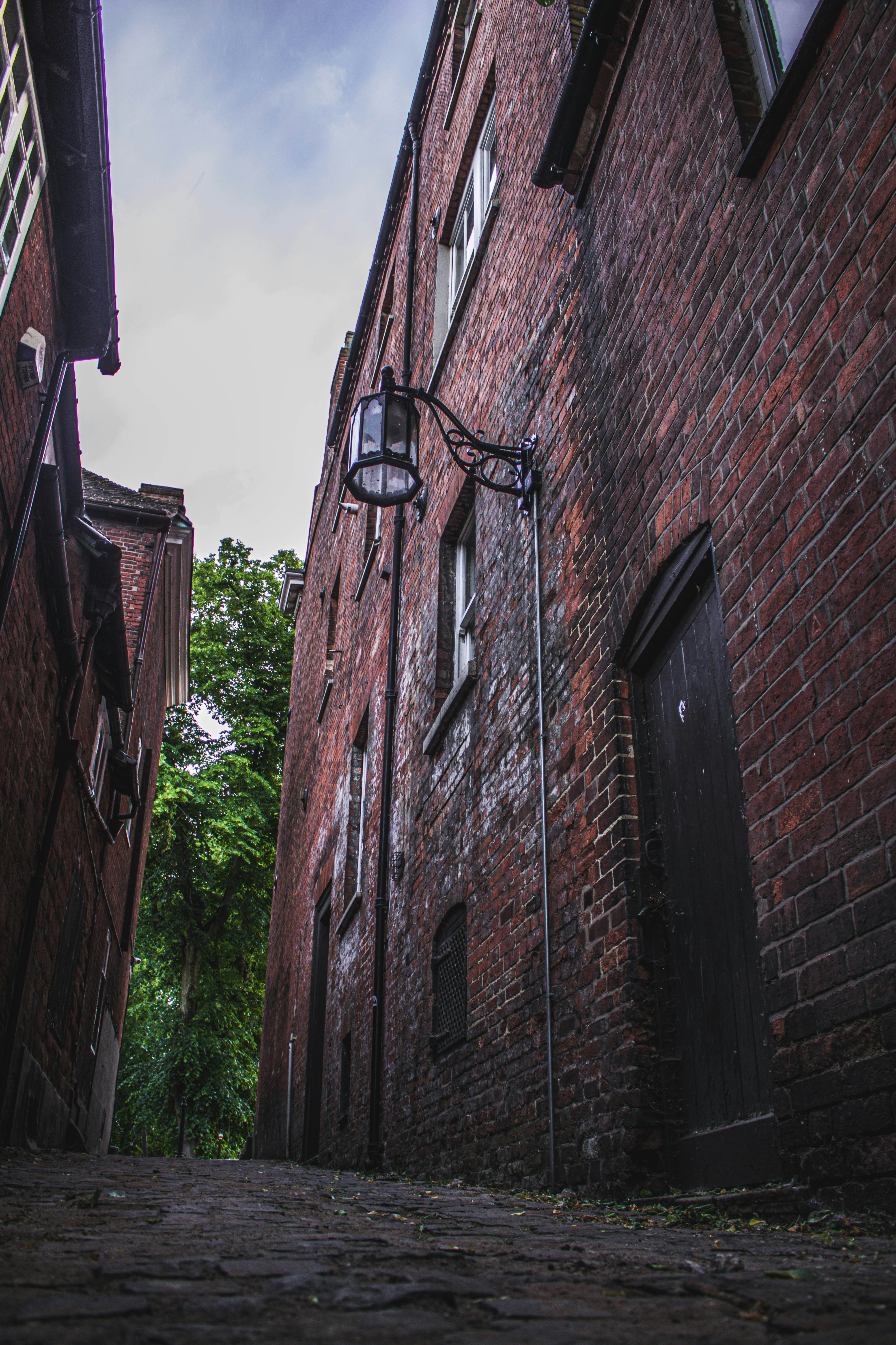 Stone-paved street in Coventry with old buildings | brown brick wall with green vines