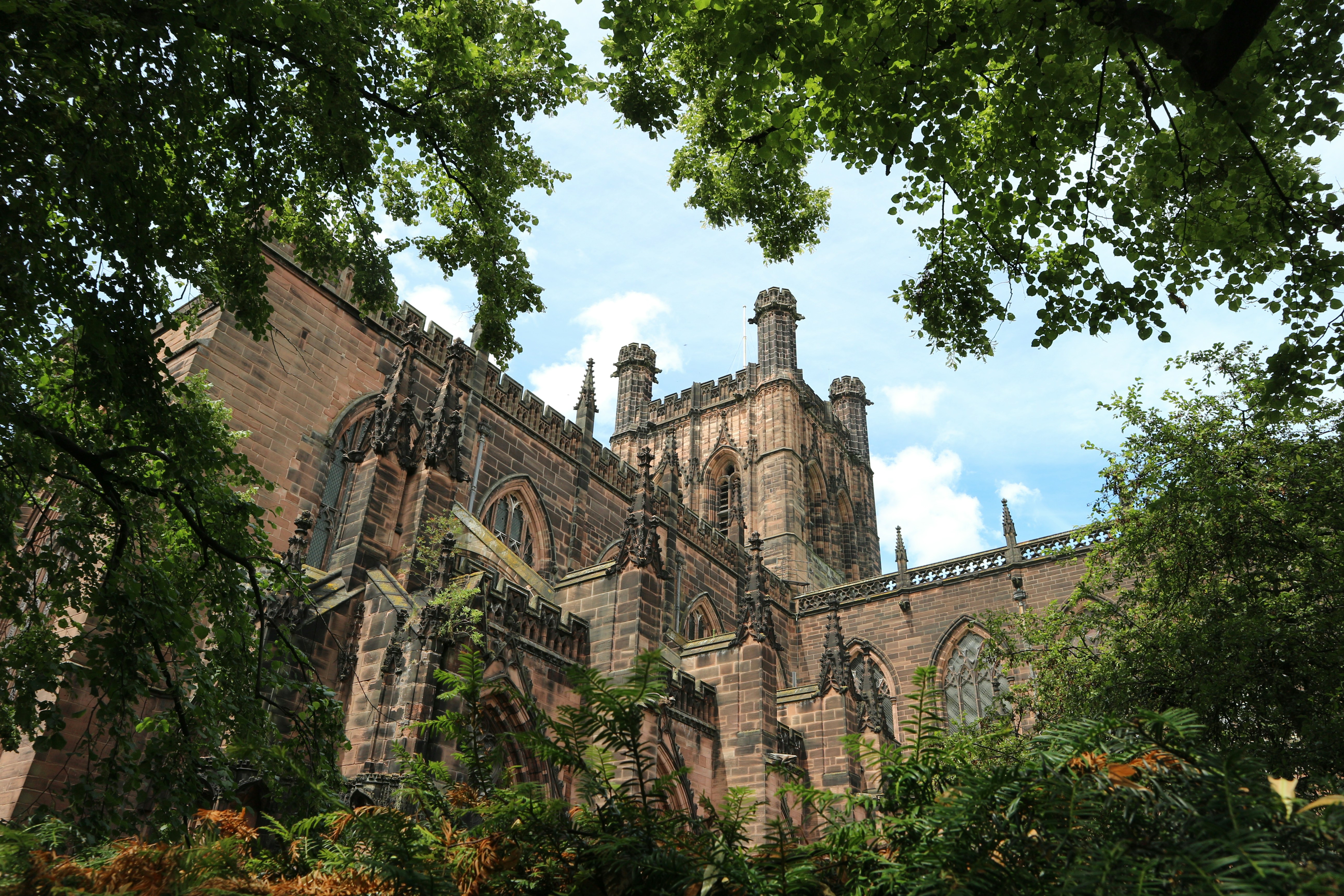 Gothic cathedral framed by lush green trees under a bright blue sky.