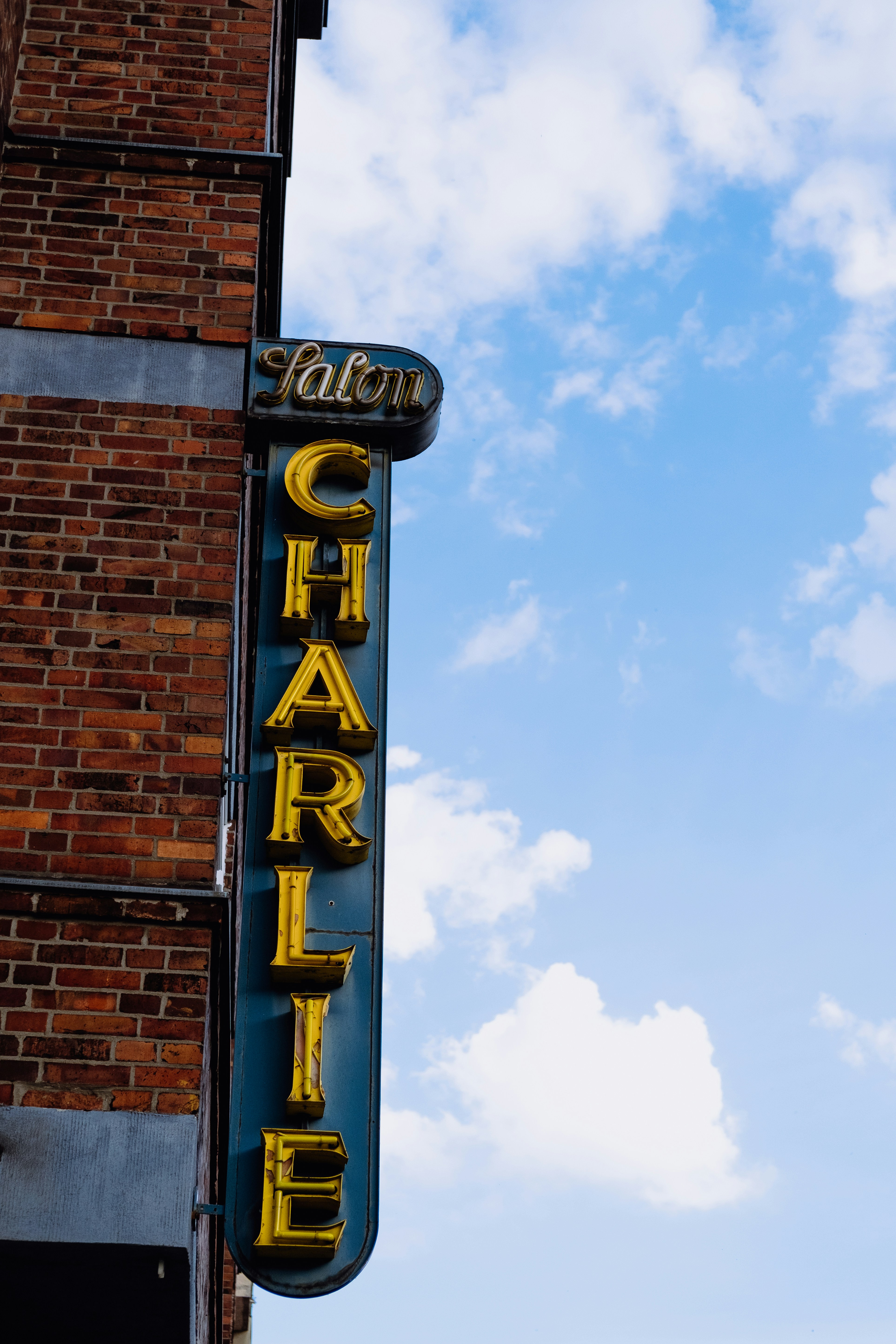 Charlie Neon on Brick: A Vertical Sign Reaching Toward the Sky