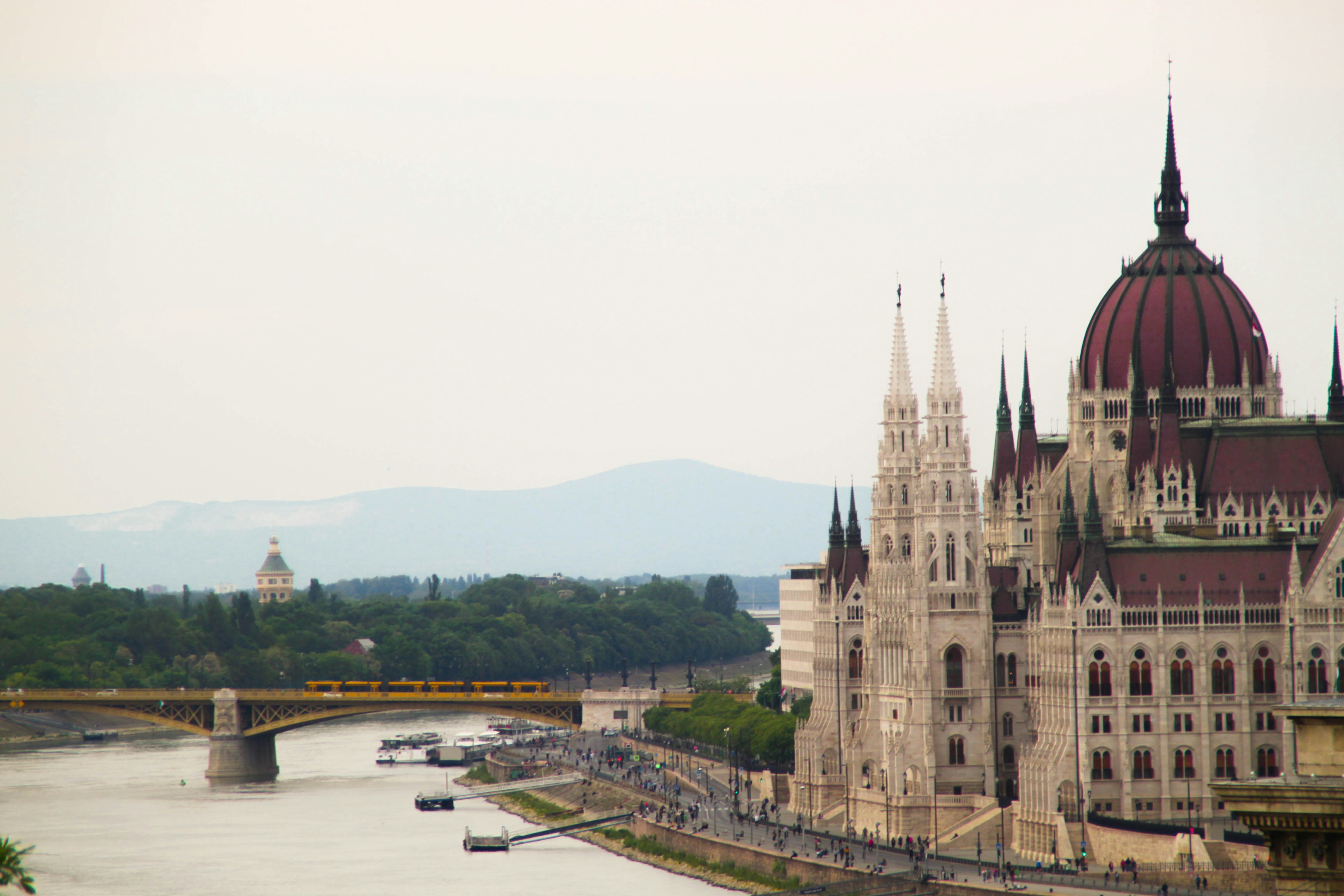 Majestic Hungarian Parliament building alongside the Danube River, with the iconic Chain Bridge in the distance. A serene view capturing the essence of Budapest's architectural beauty.