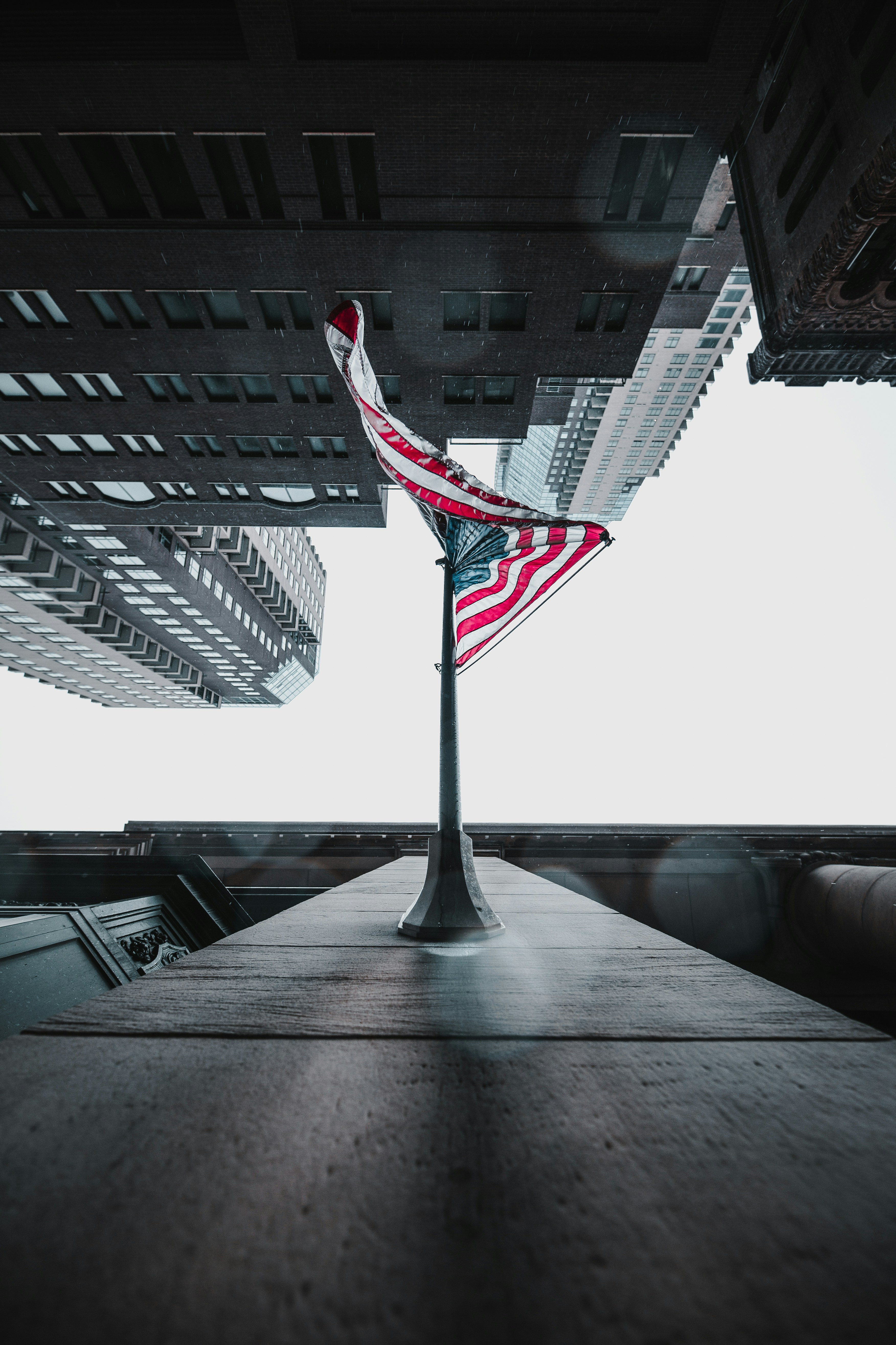 Flag Between Steel Giants: A Rooftop Portrait in Gray Heights
