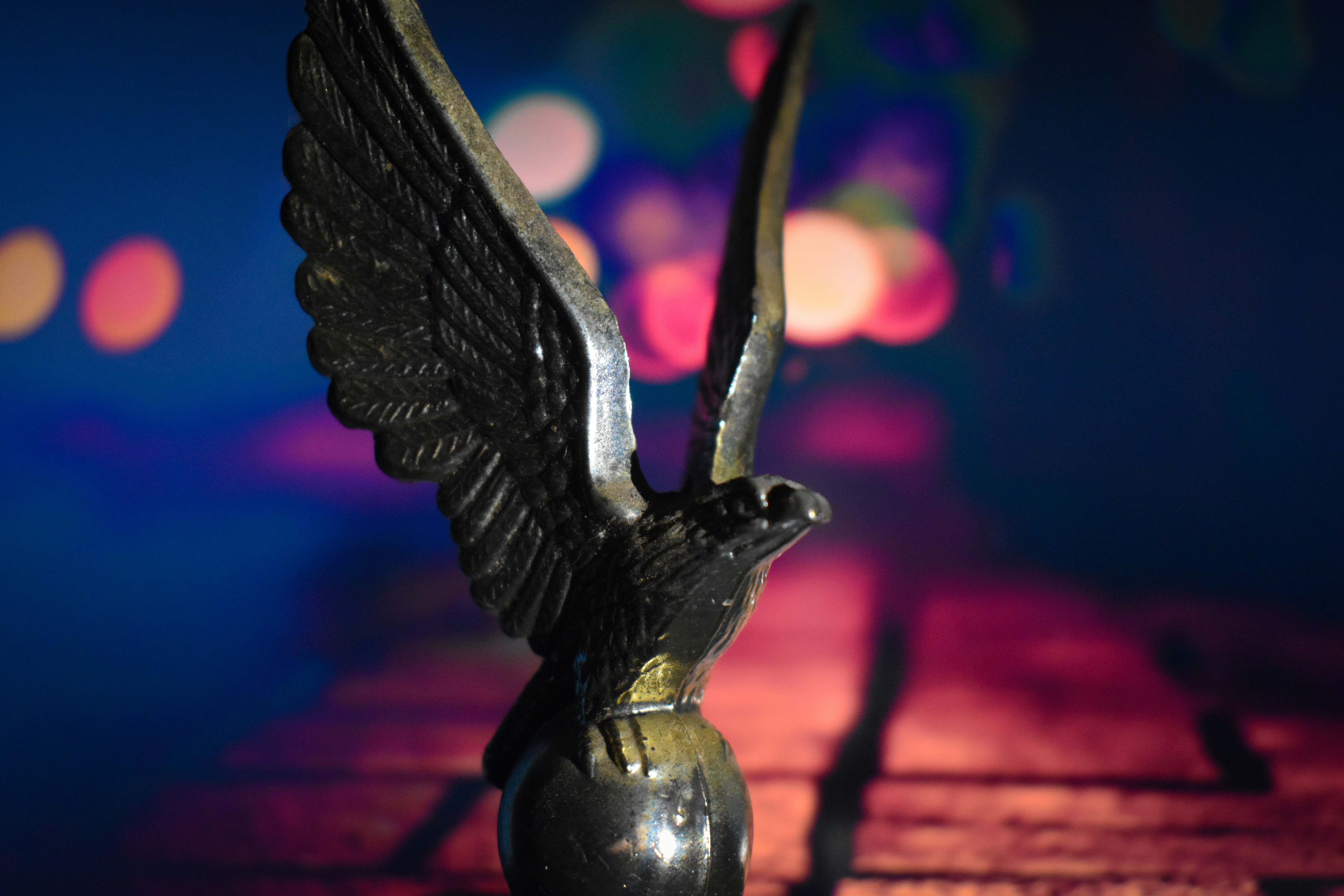Winged finial rising from a rain-soaked pier into bokeh dusk