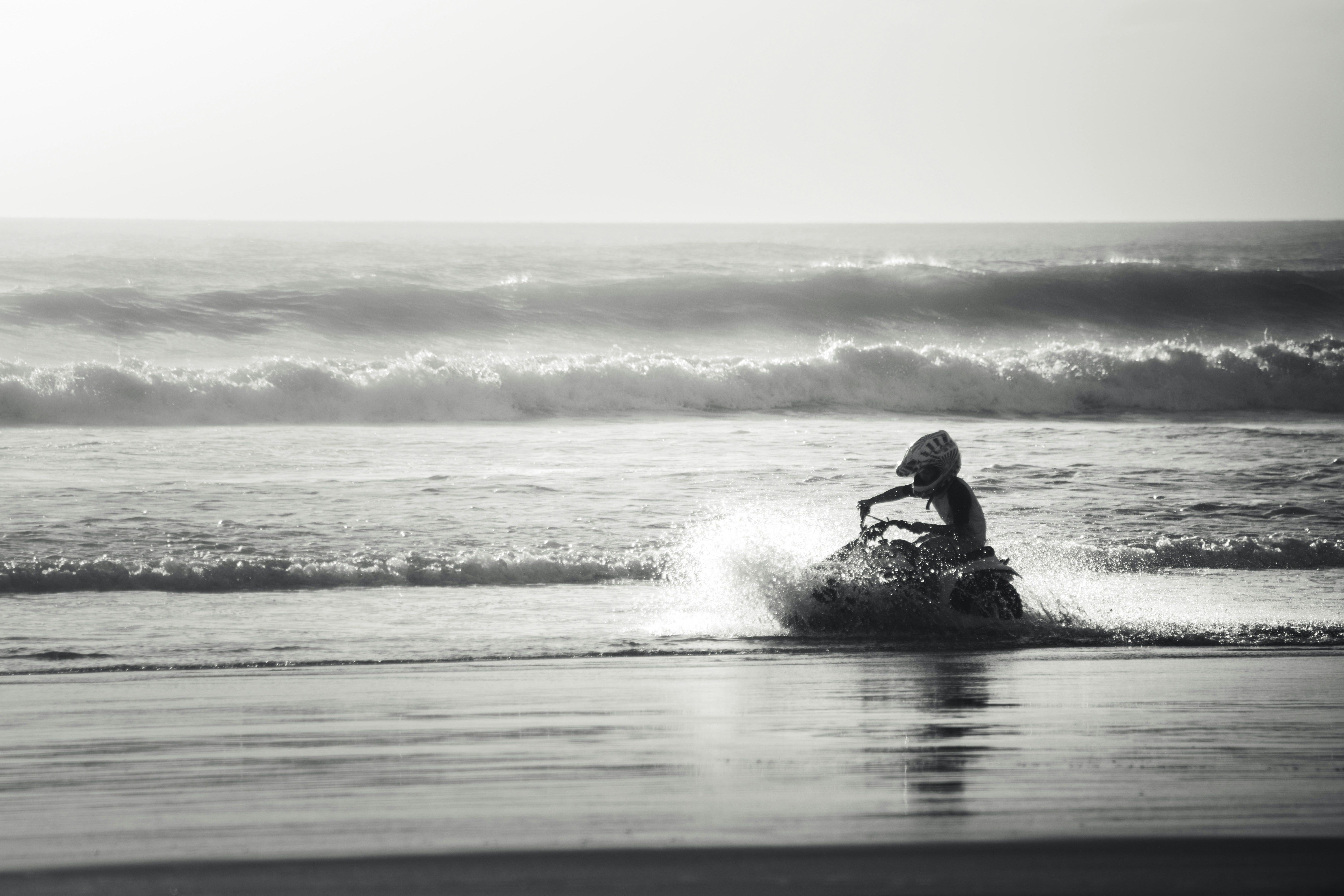 A child navigating the surf on a jet ski, creating splashes against the backdrop of rolling waves.