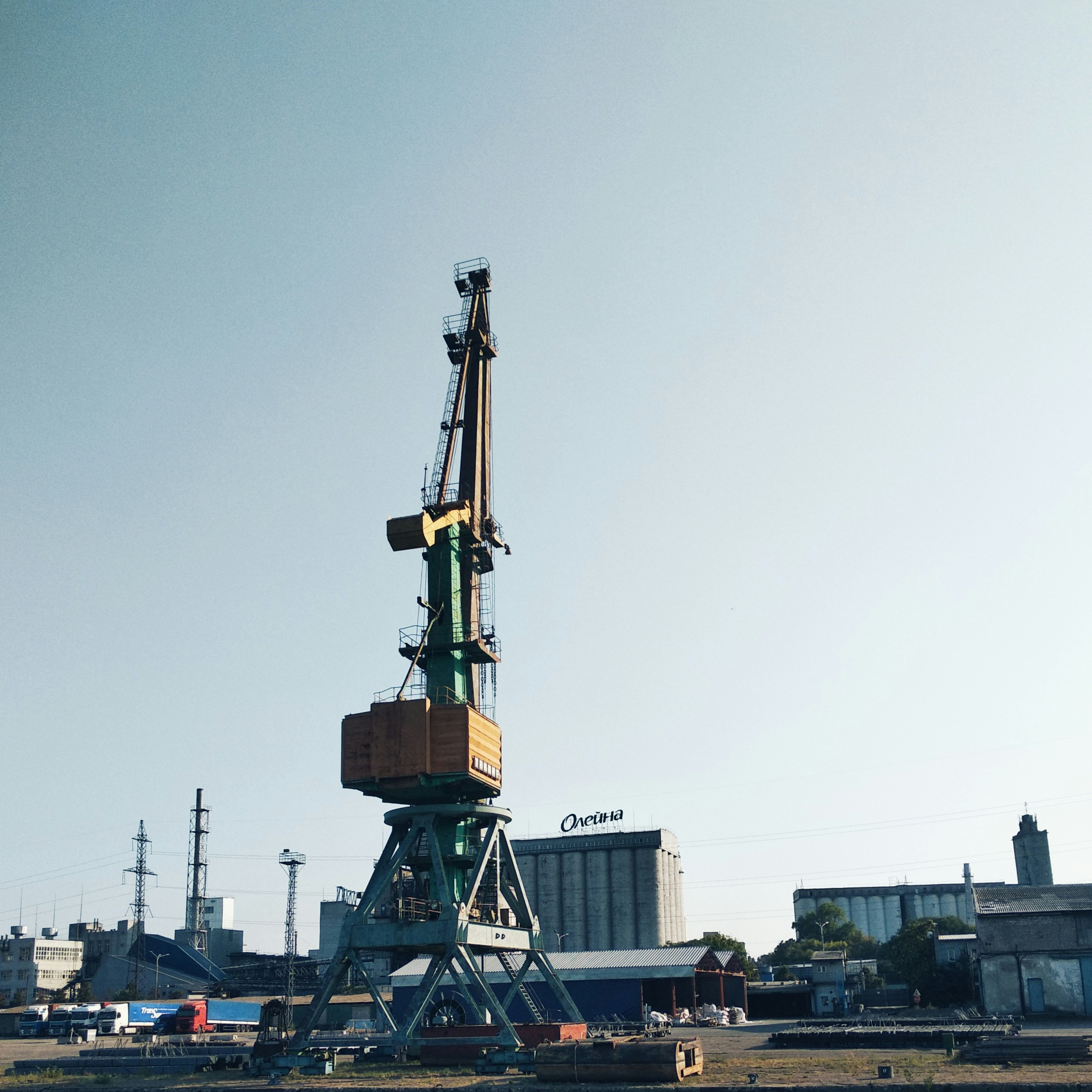 A towering industrial crane stands prominently against a clear sky, symbolizing the heart of commerce and construction. The scene captures the essence of urban infrastructure.